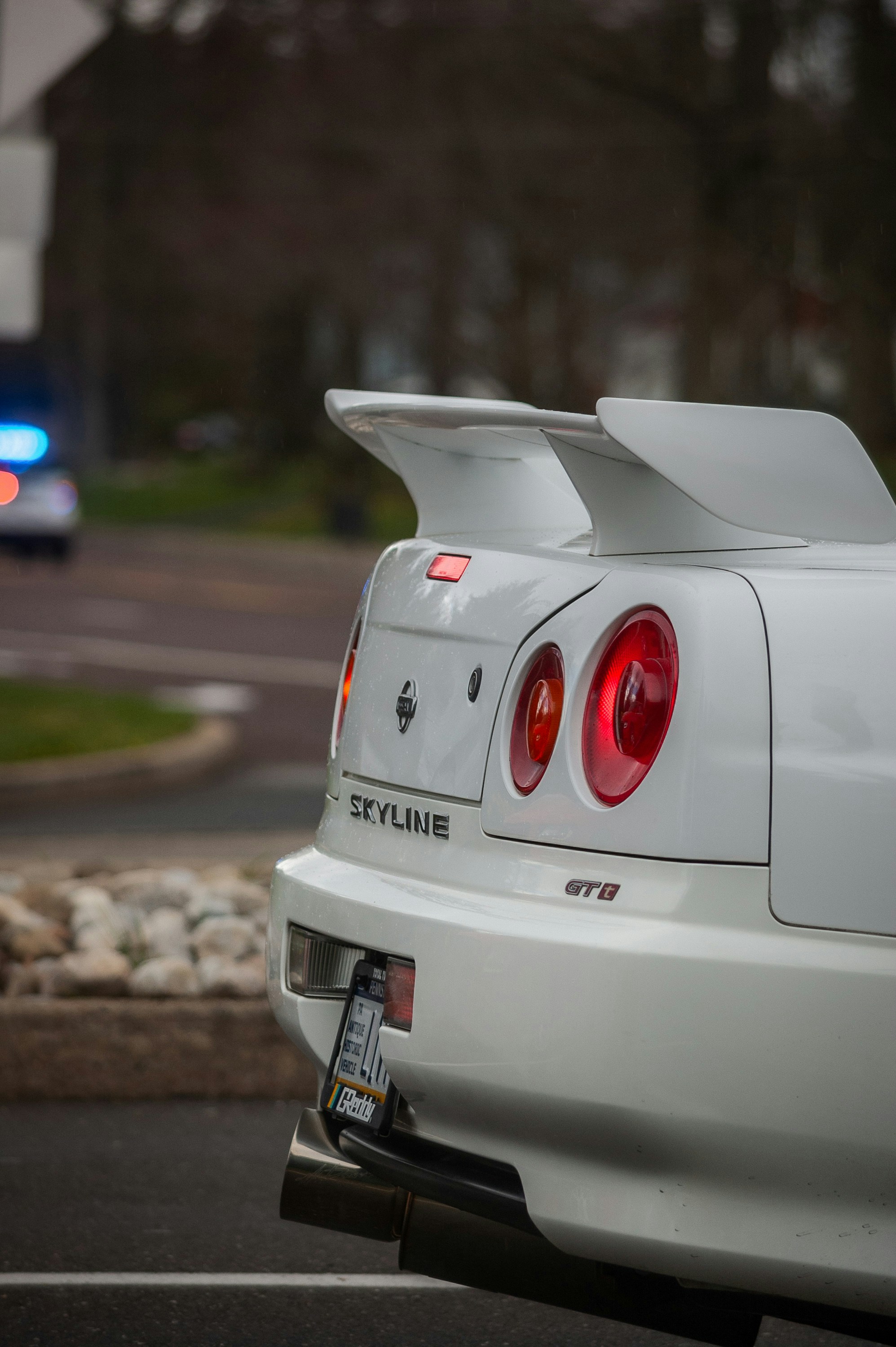 Rear-Quarter of a White Nissan Skyline GT-R R34: Clean lines and red taillights in a parking-lot setting
