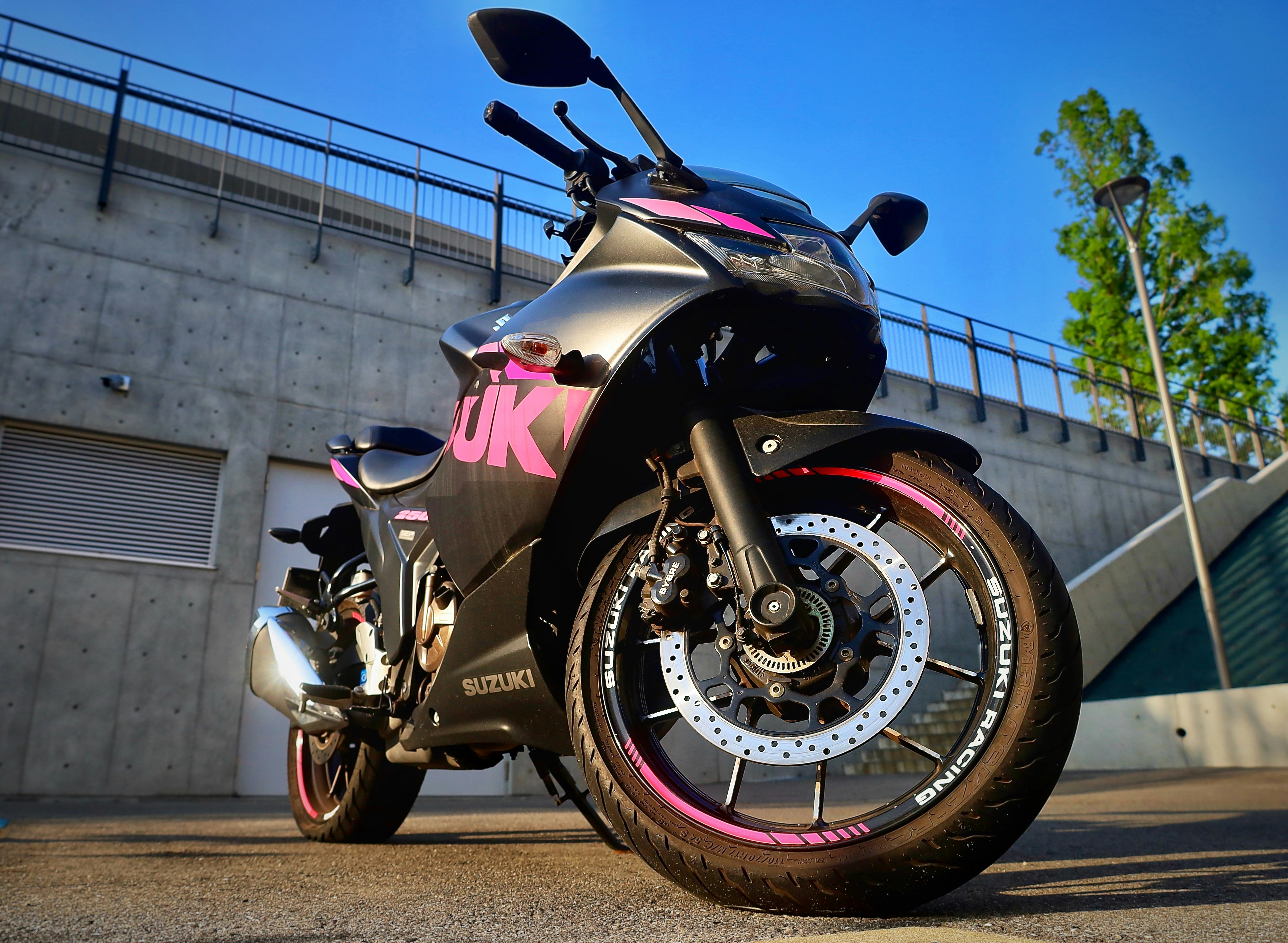 Magenta-Accented Suzuki Sportbike: A Low-Angle Standout Against Urban Concrete
