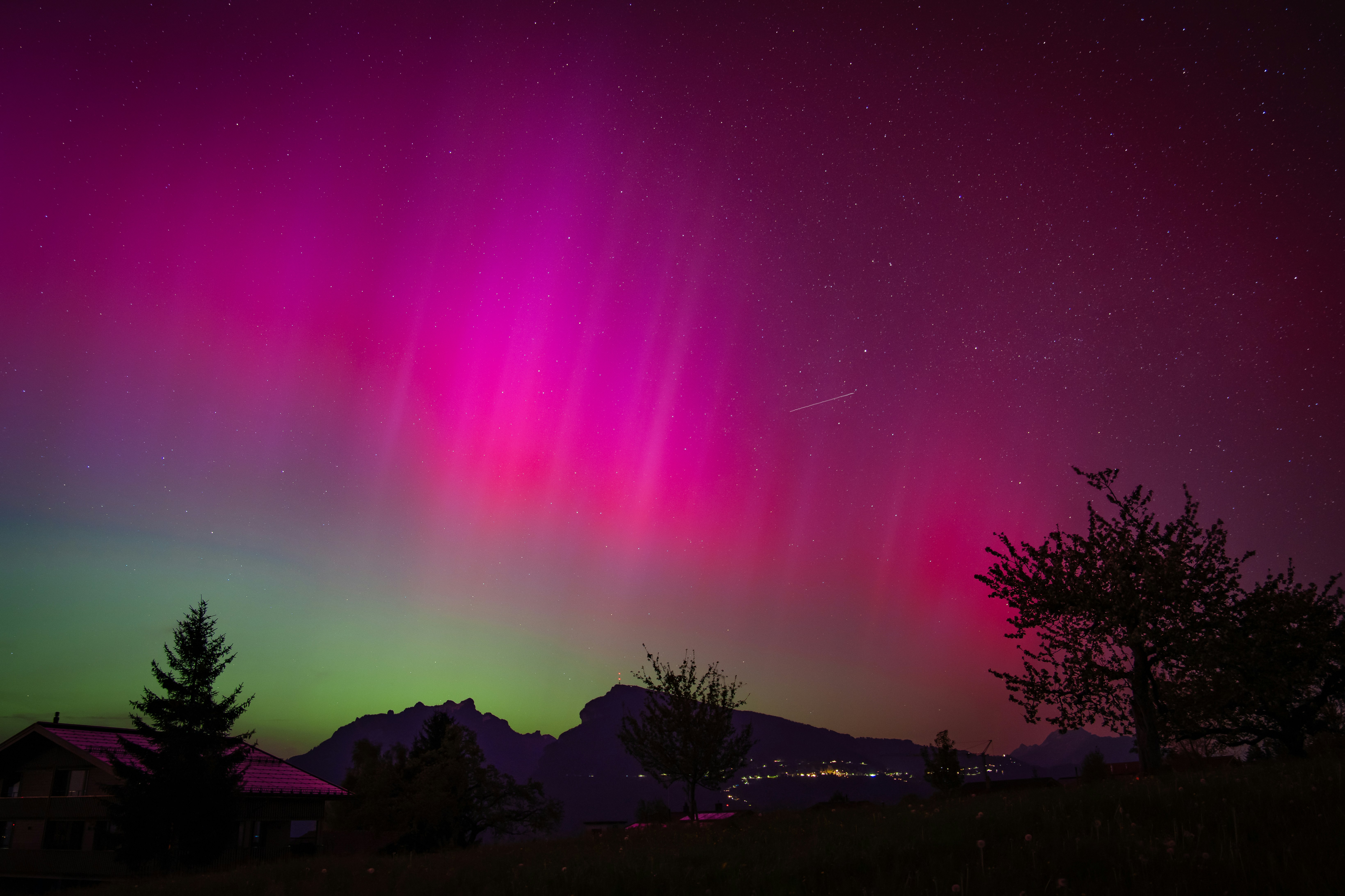 Vibrant auroras illuminate the night sky above a serene landscape, blending shades of purple and green with twinkling stars. A tranquil scene that showcases nature's artistry.