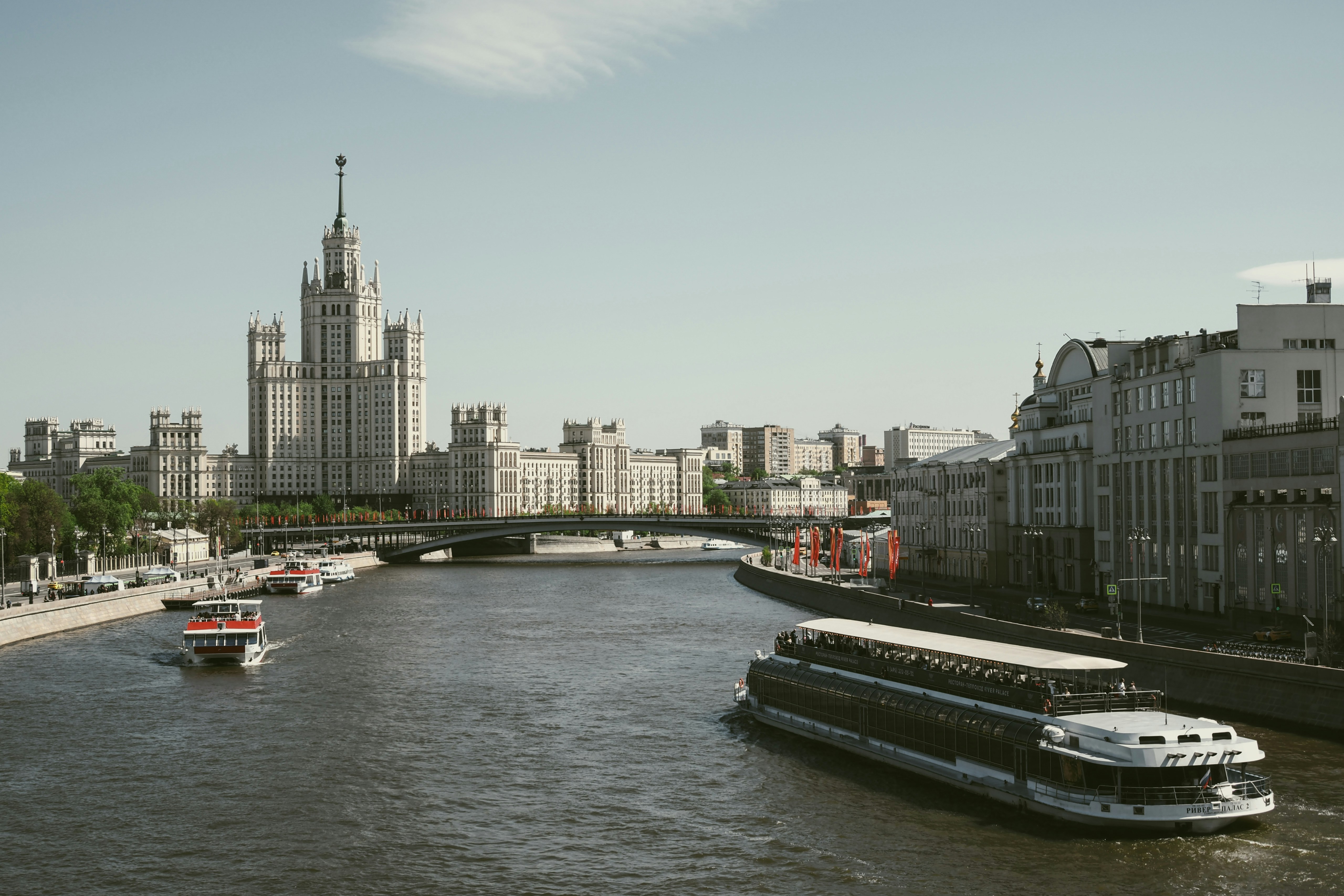 Riverside Confluence: A Clocktower and Boats Along the Moskva-like Skyline