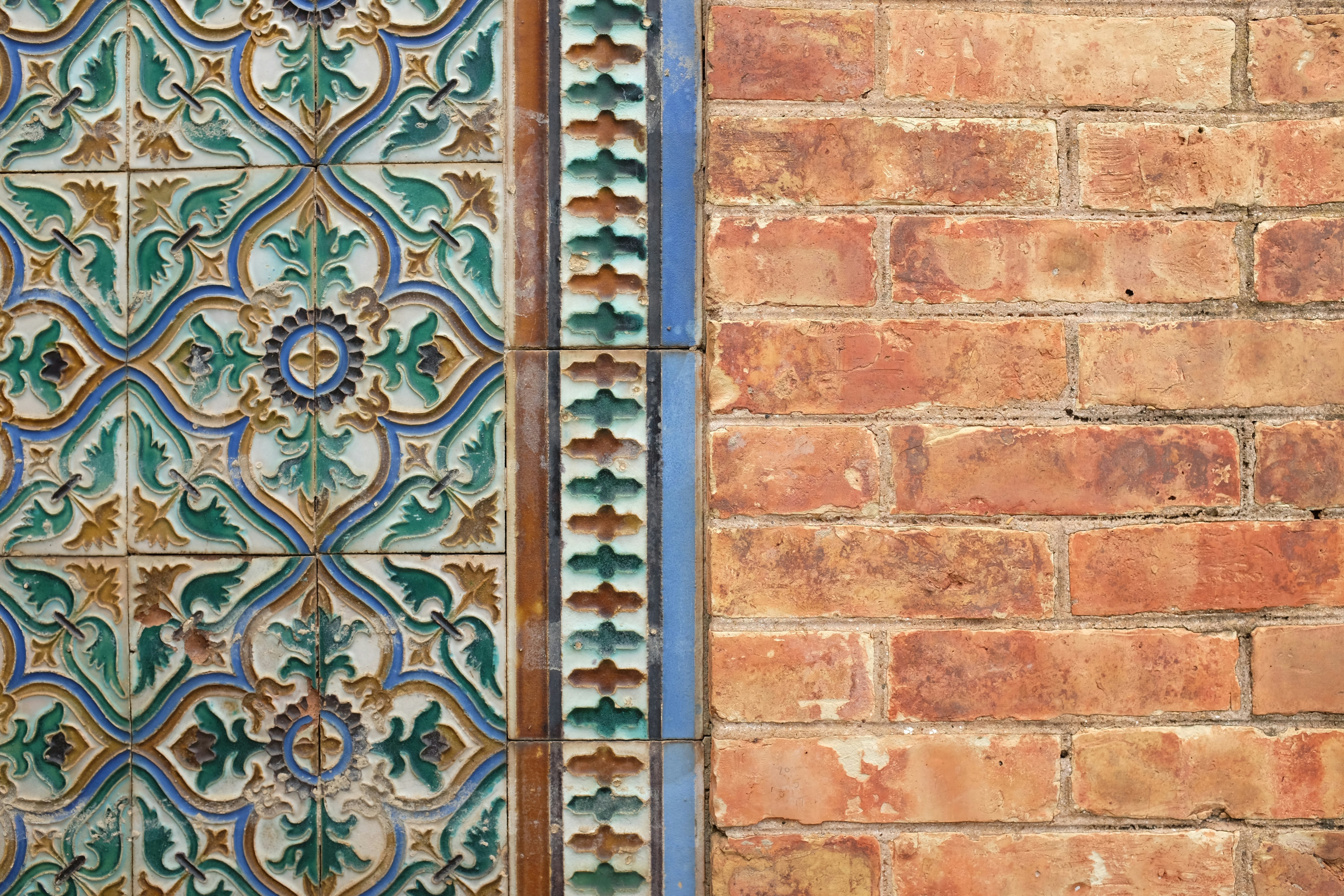 Ornate Spanish tilework juxtaposed with rustic brick wall.