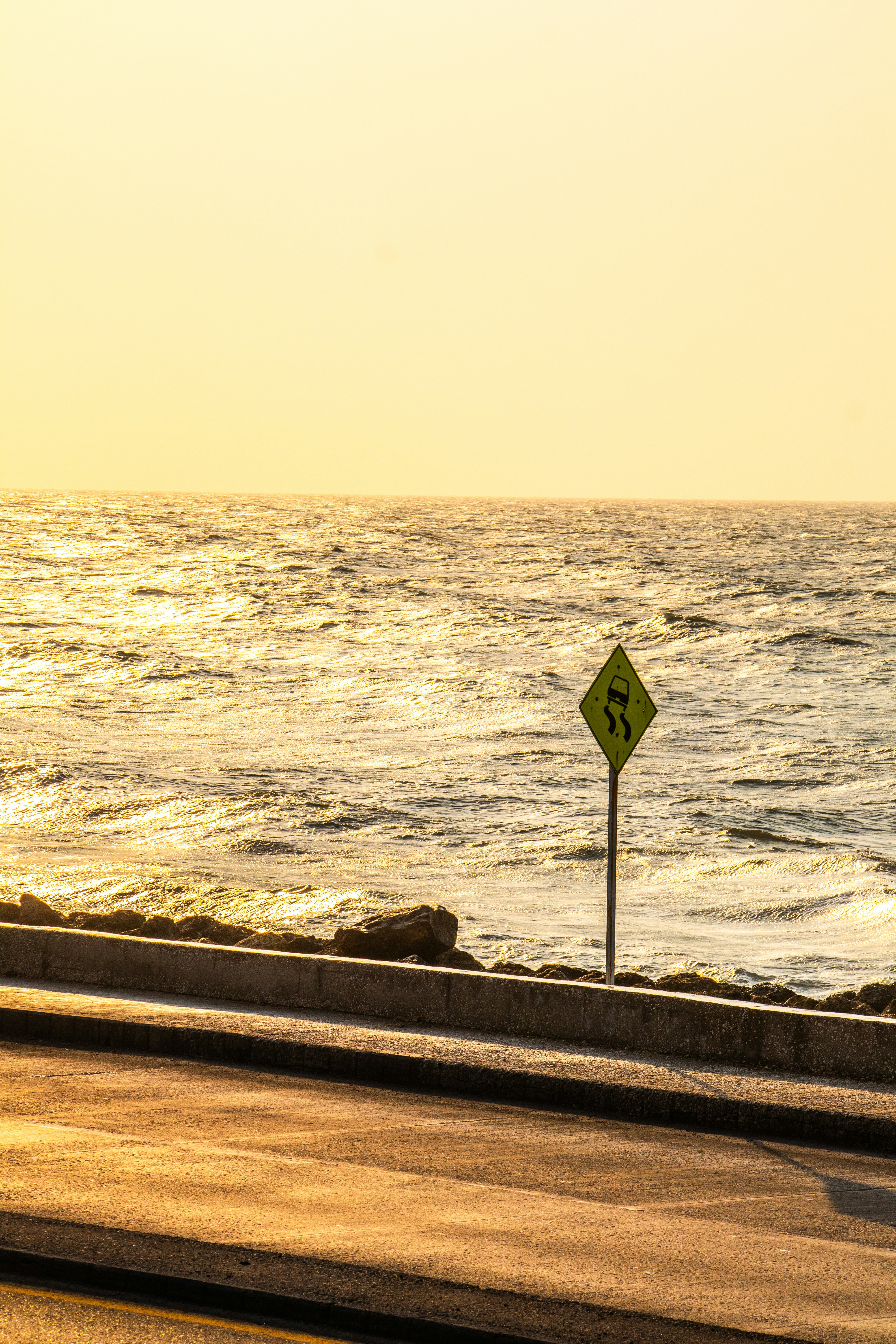 Golden Hour by the Seaside: A Quiet Pedestrian Walk Sign Against the Looming Horizon