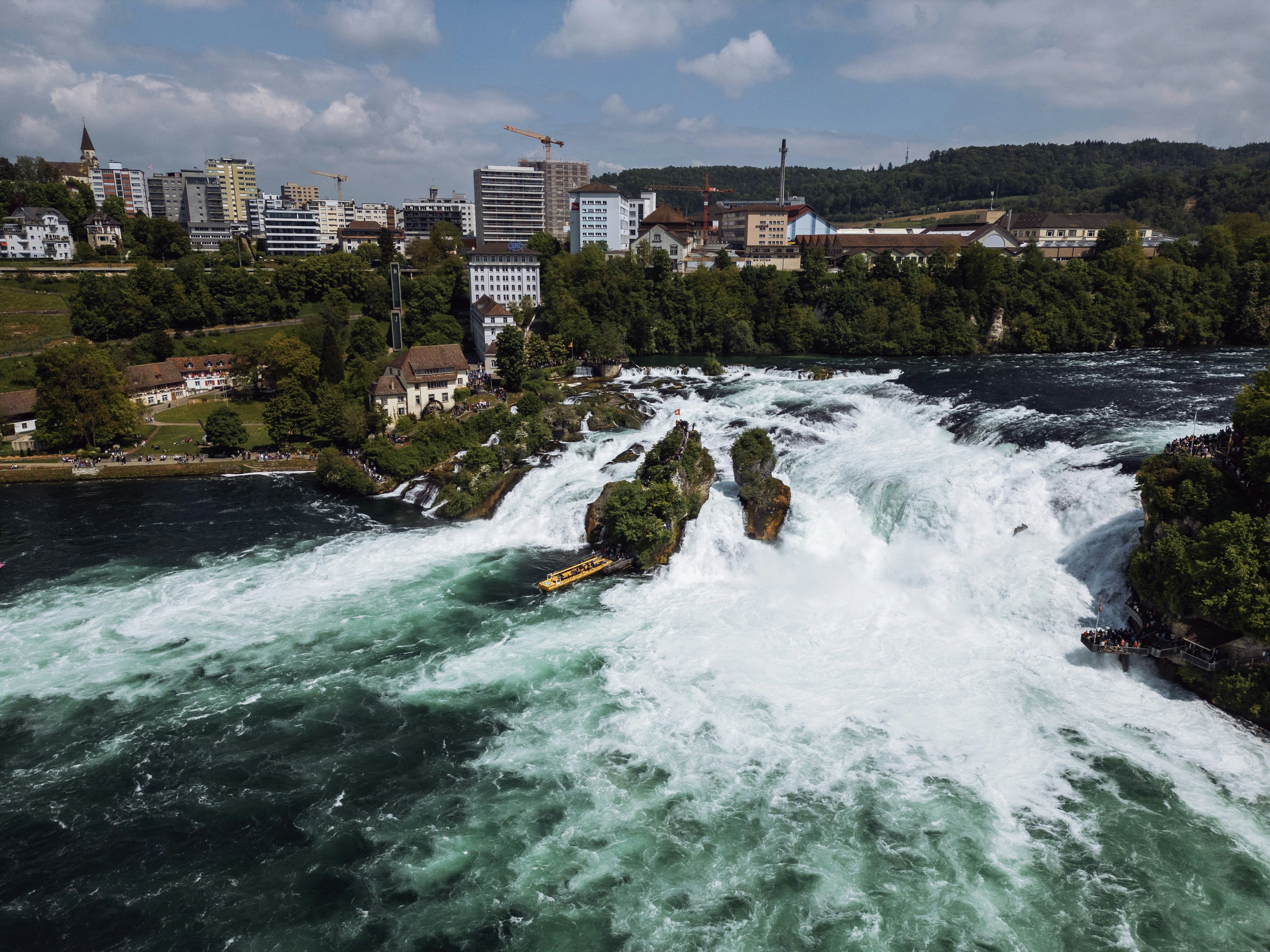 A view of a river with rapids and a city in the background photo – Free ...