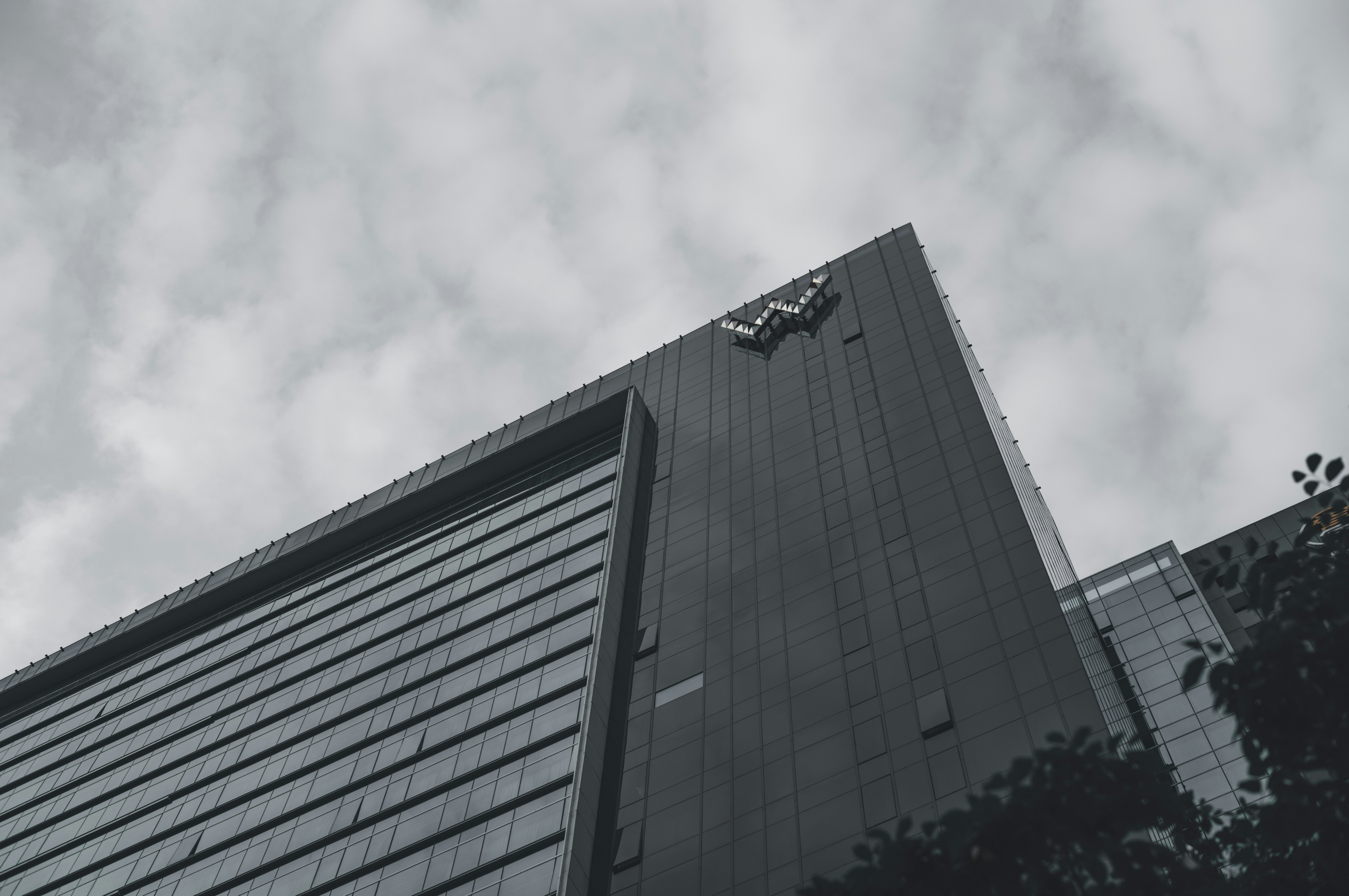 Glass Sliver Against a Cloudy Sky: A Low-Angle Tower in Mono
