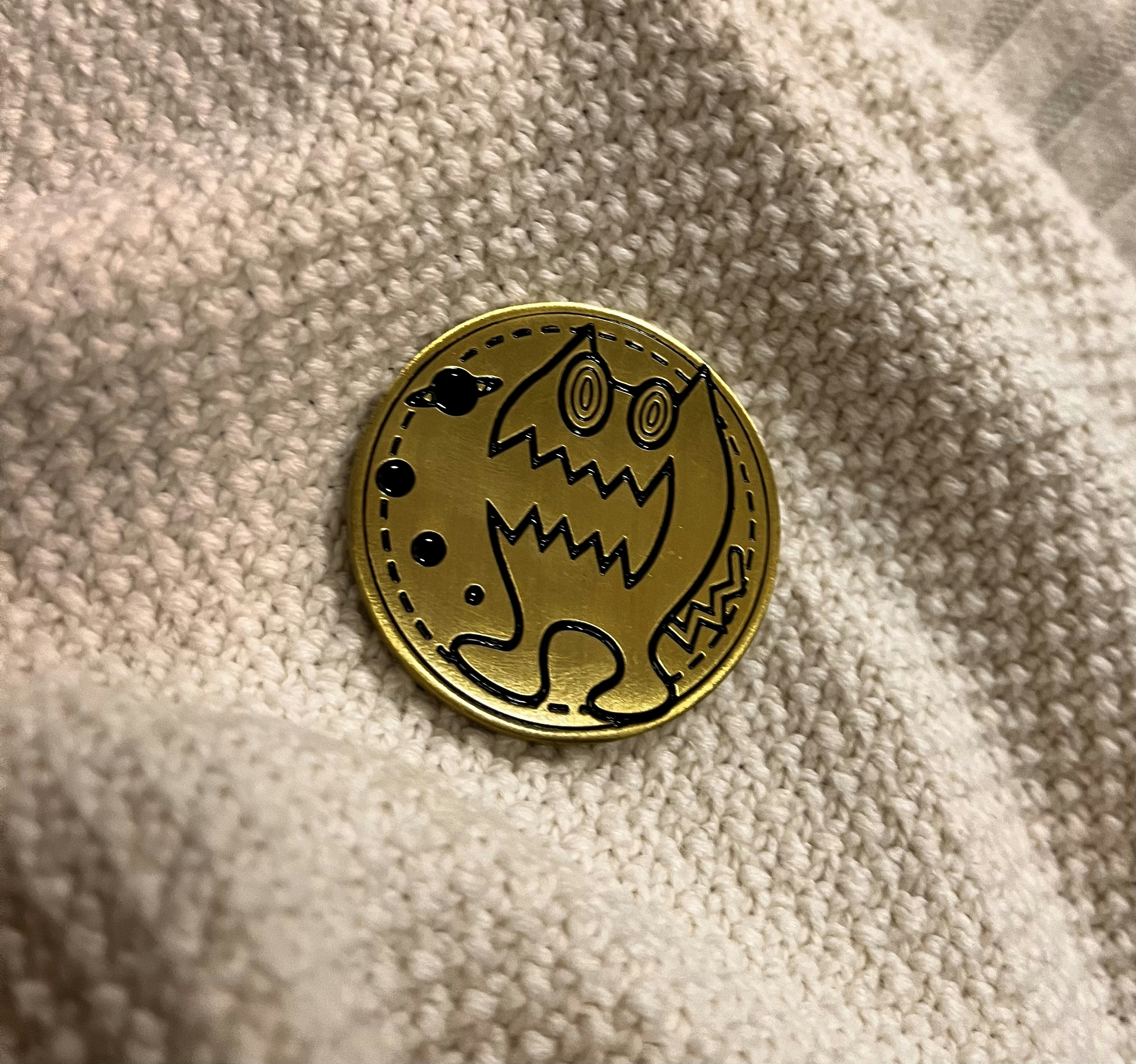 Cartoon Monster on a Golden Token Resting on Knit Fabric