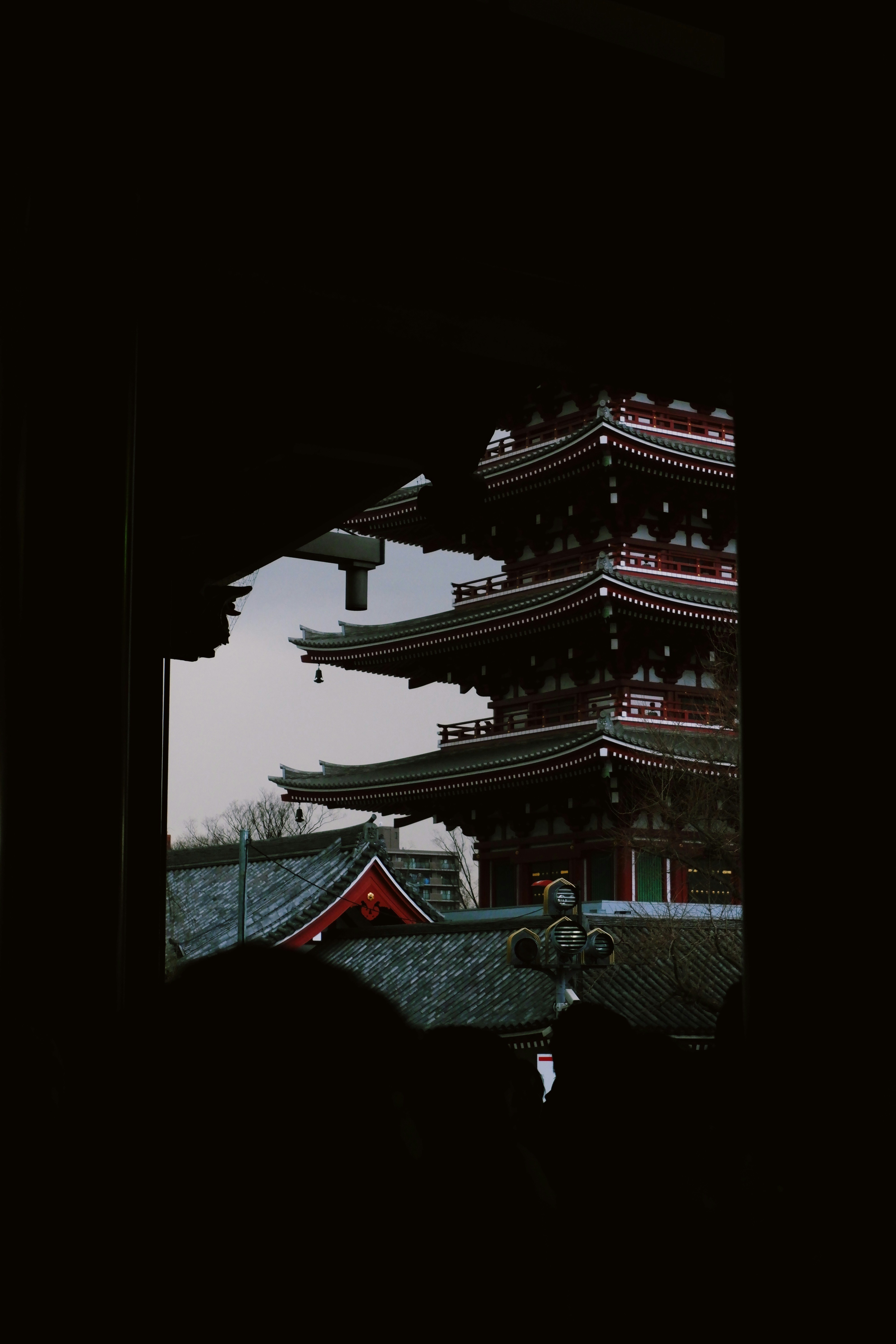 Through a Shadowed Frame, the Red-Tier Pagoda Emerges in Quiet Daylight