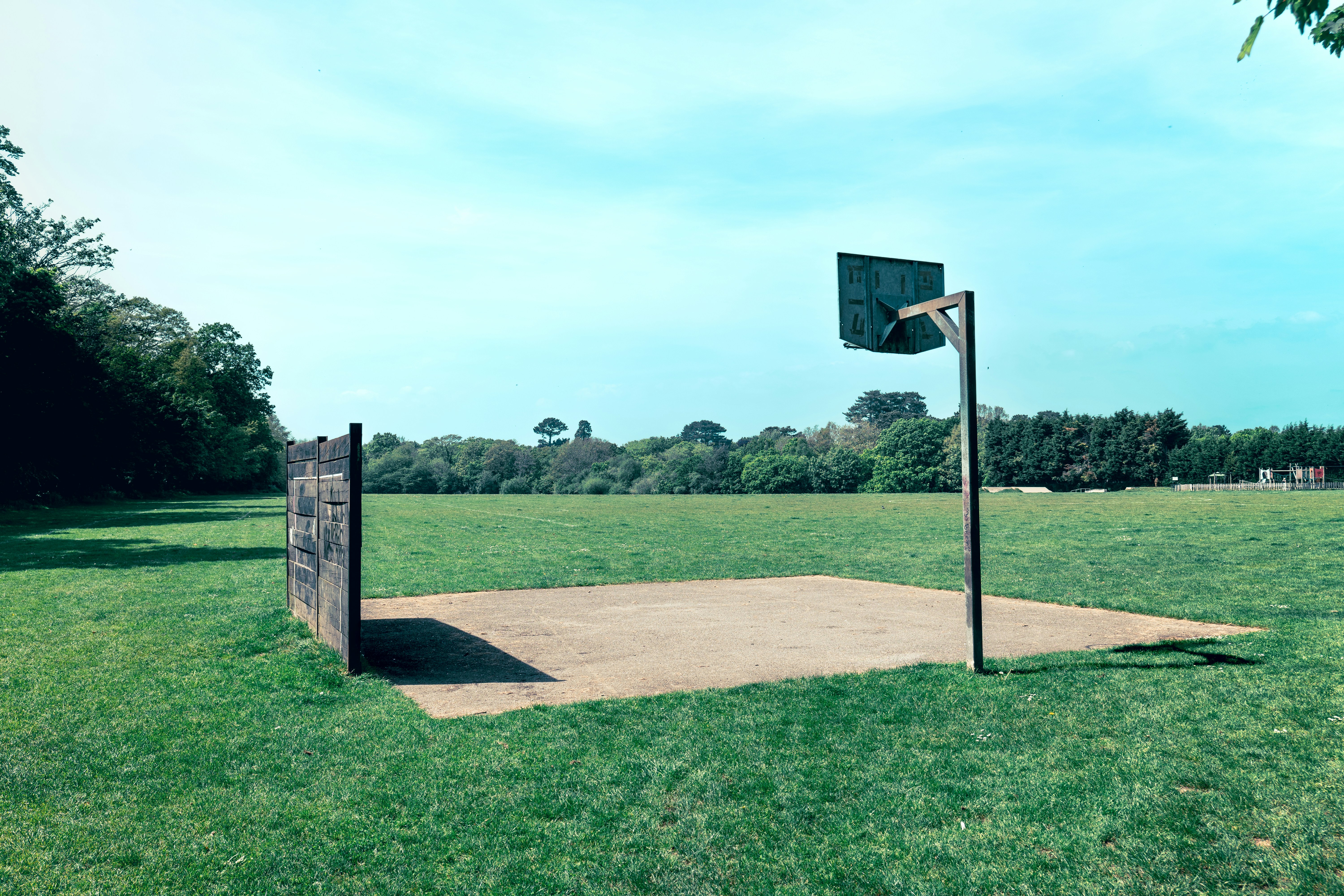 Lone Hoop Under a Wide Blue Sky: A Quiet Park Court