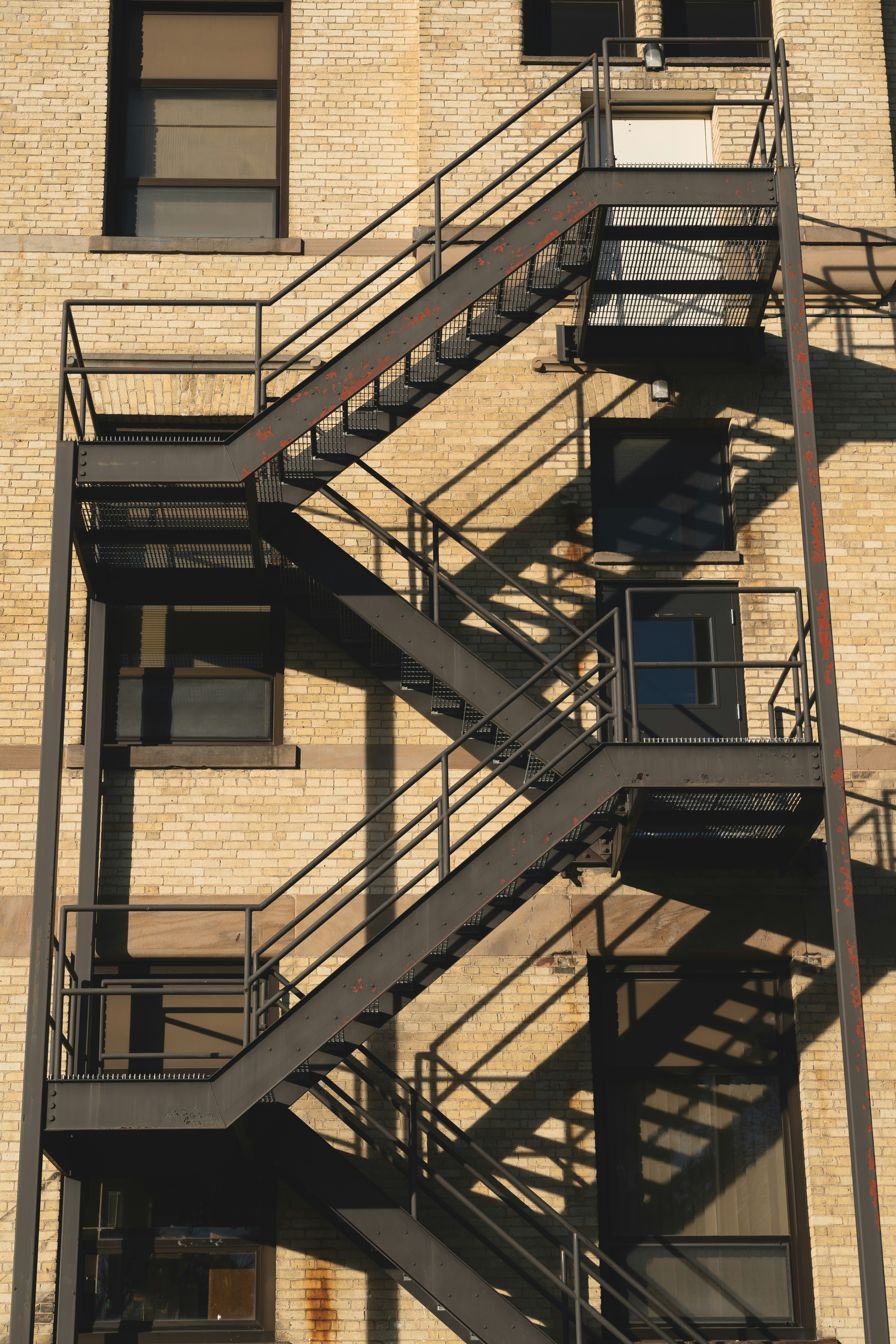 A tall building with a fire escape next to it photo – Free Brick Image ...