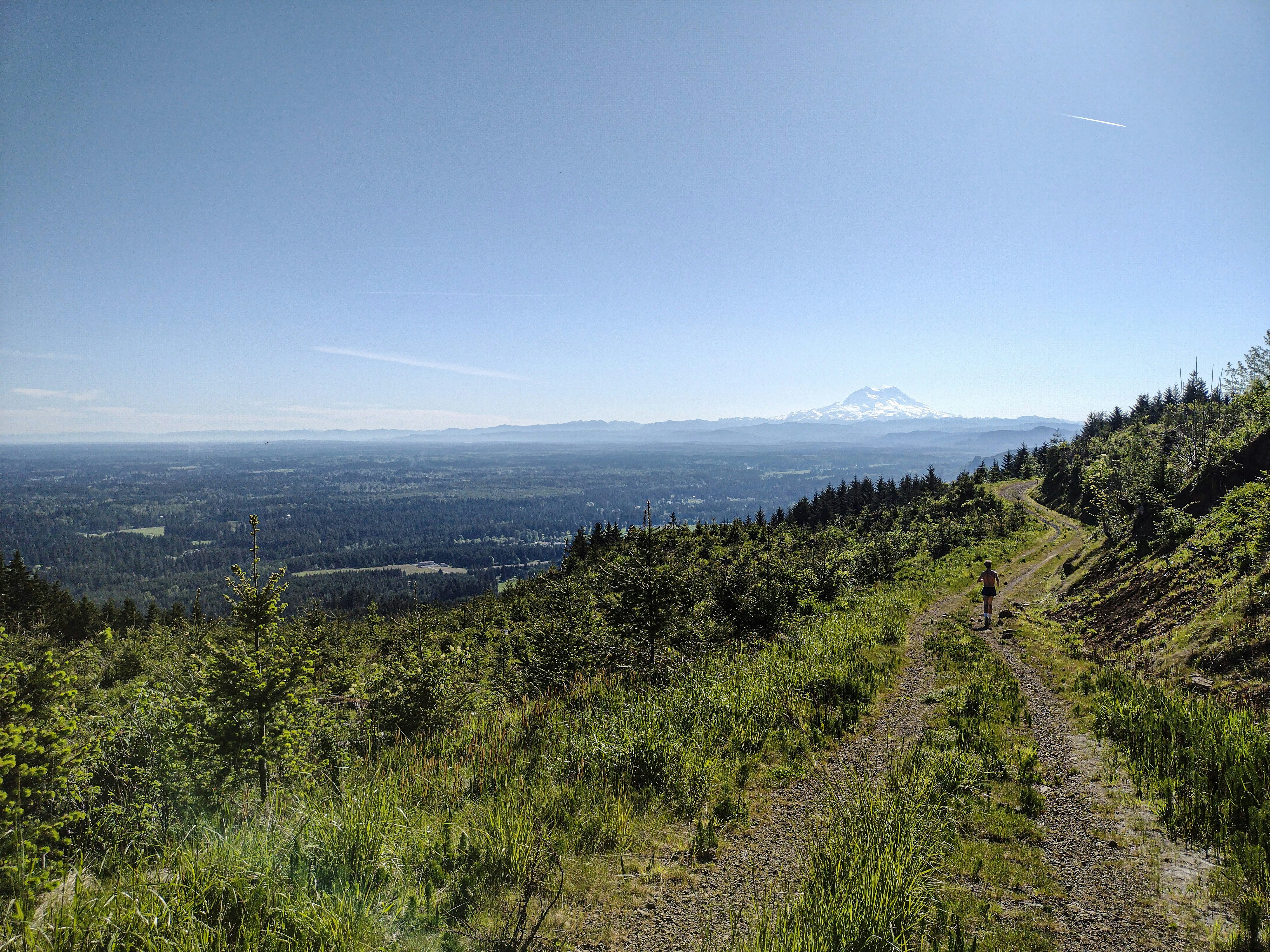 Ridge Trail Under a Clear Sky: Lone Hiker En Route Toward a Snow-Capped Peak