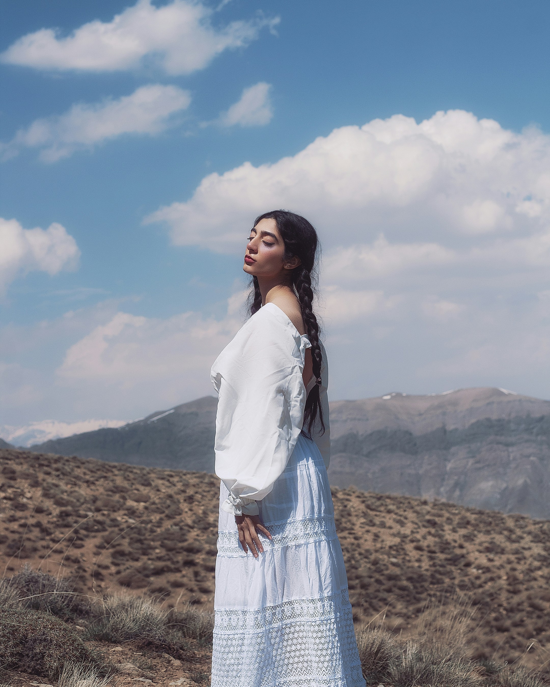 a woman in a white dress standing on a hill