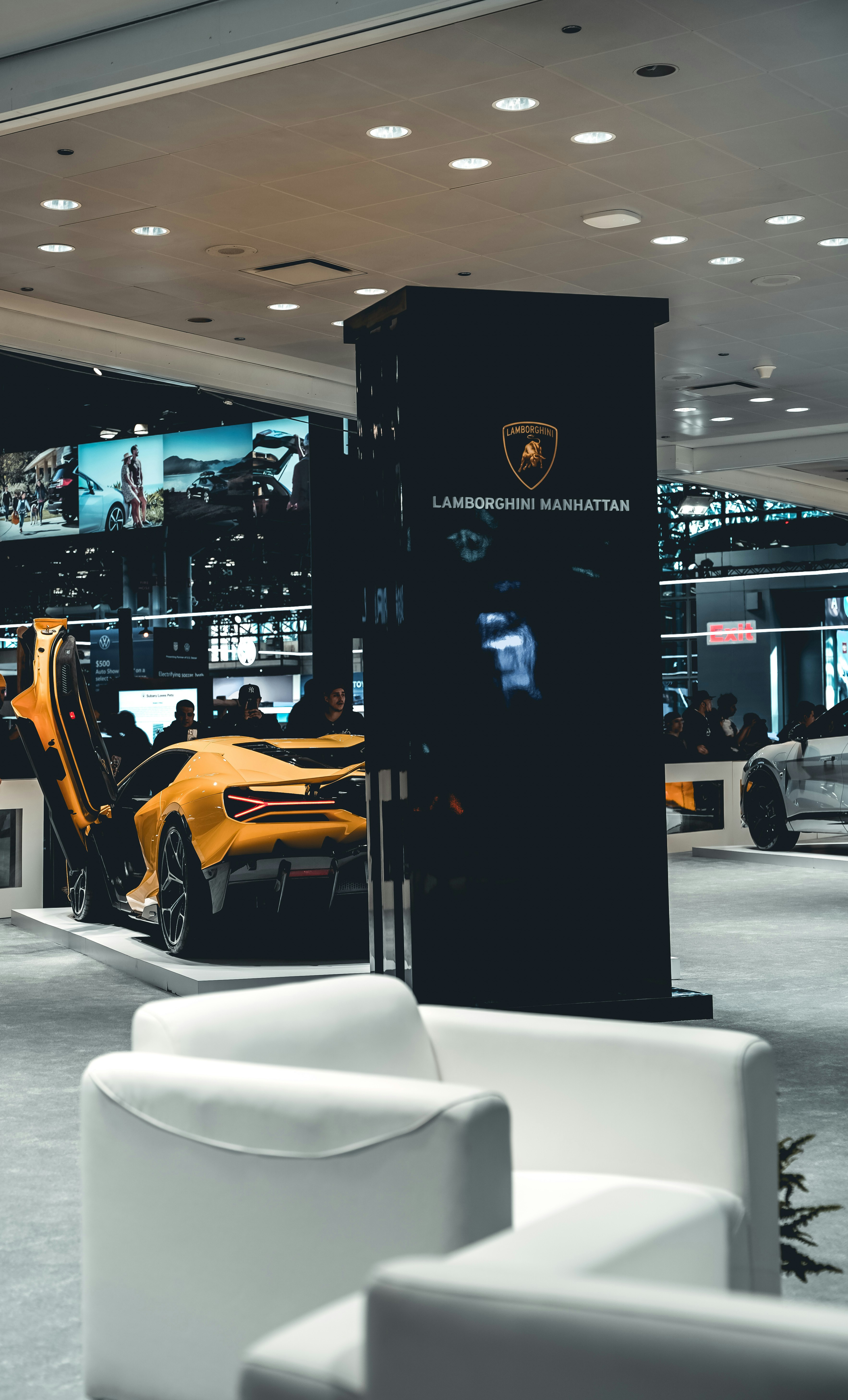 Yellow Lamborghini Emerges from the Shadows of a Black Pillar in a Glossy Showroom