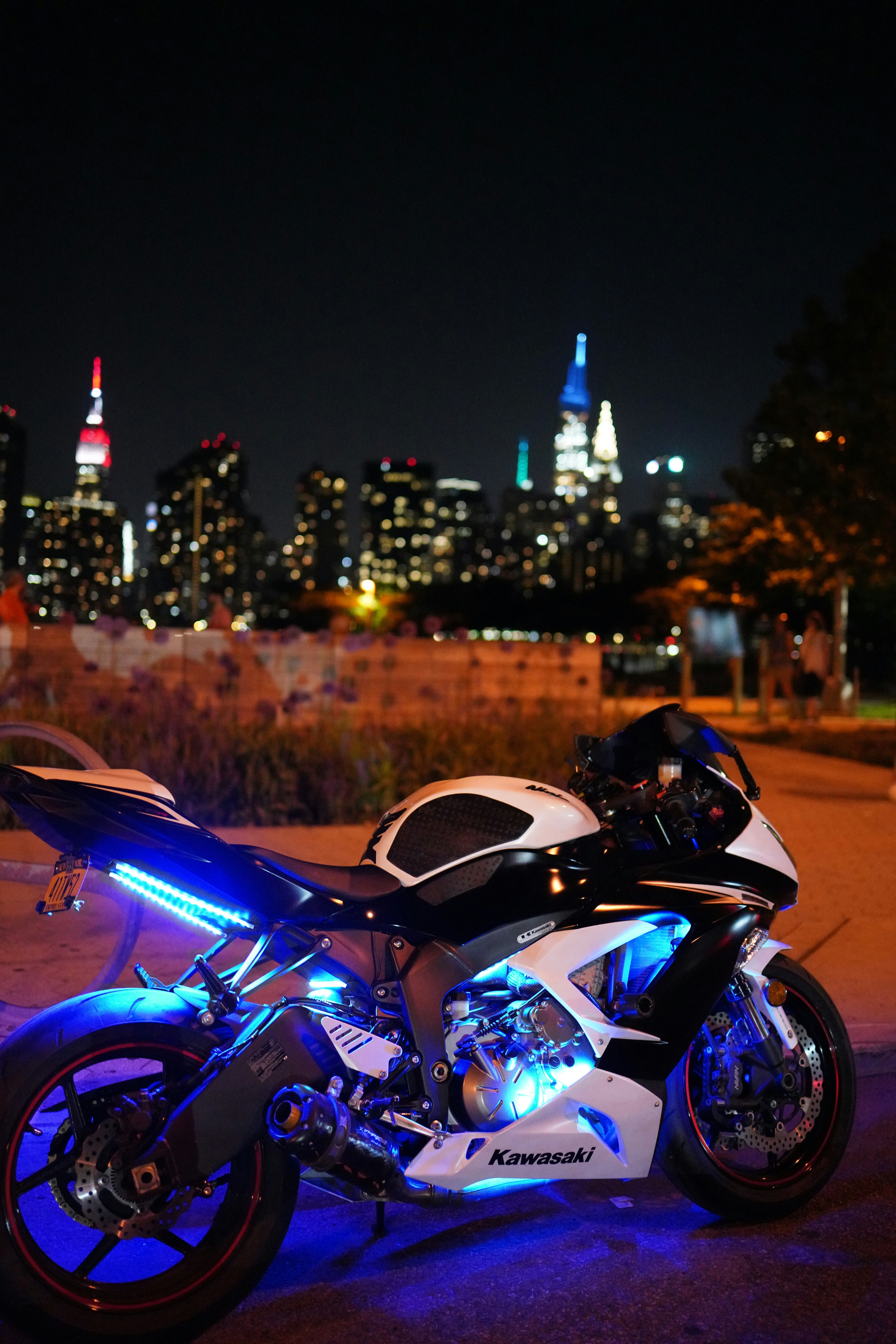 A motorcycle parked in front of a city skyline photo – Free Lighting ...