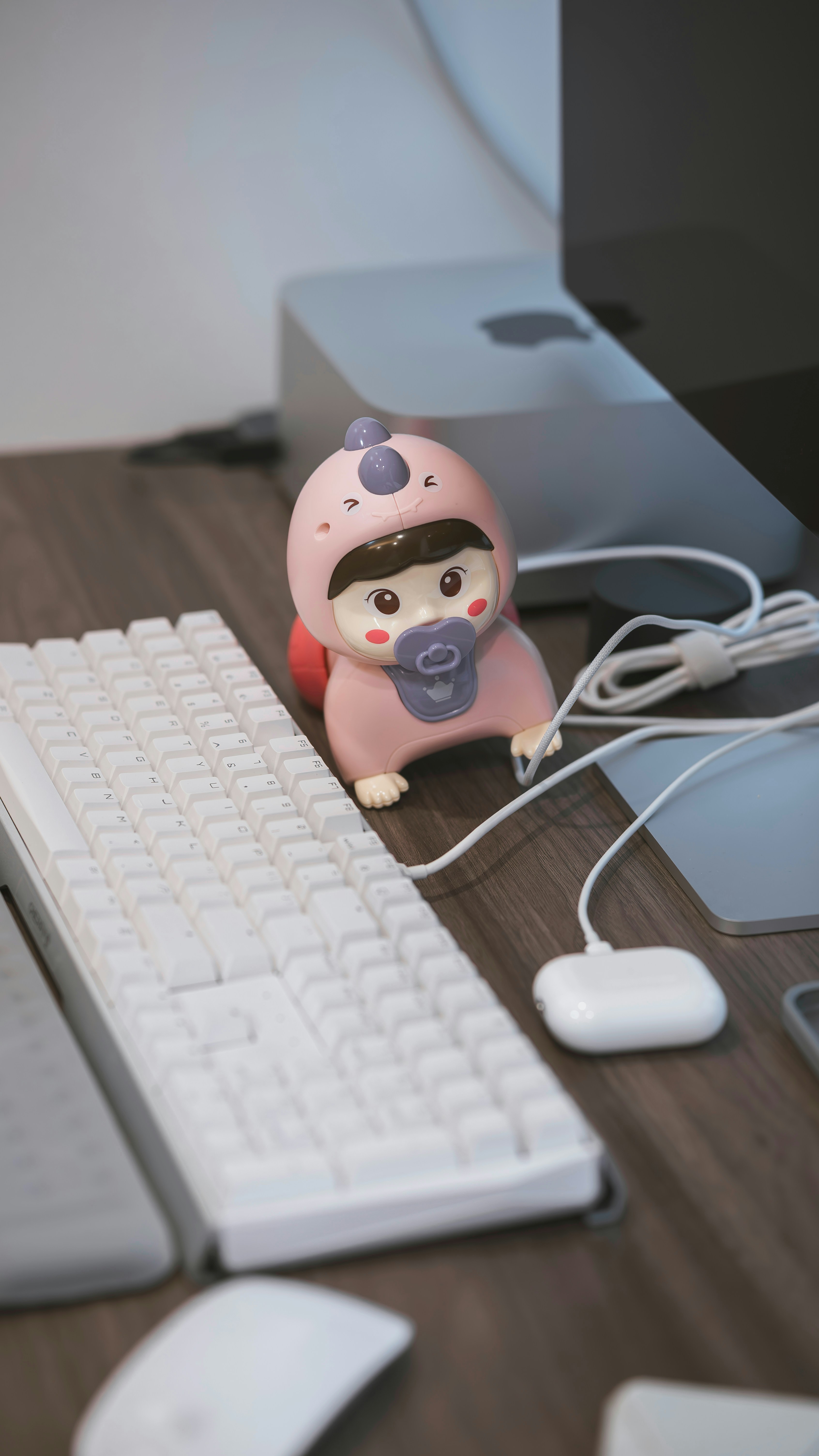Pink baby figure with pacifier amid desk setup and keyboard