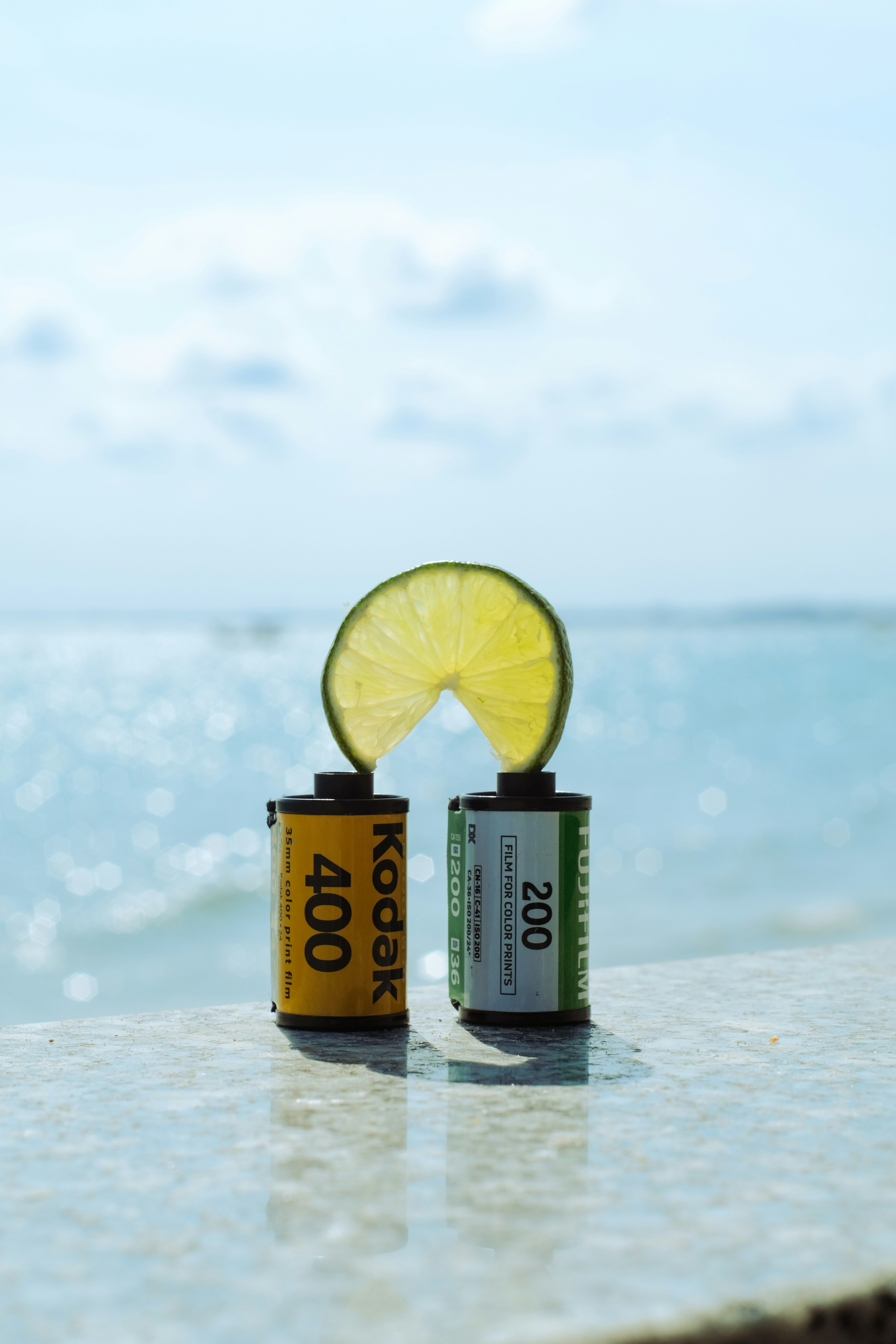 Lime Arc Crowned Kodak: a sunlit seaside still-life with vintage film canisters