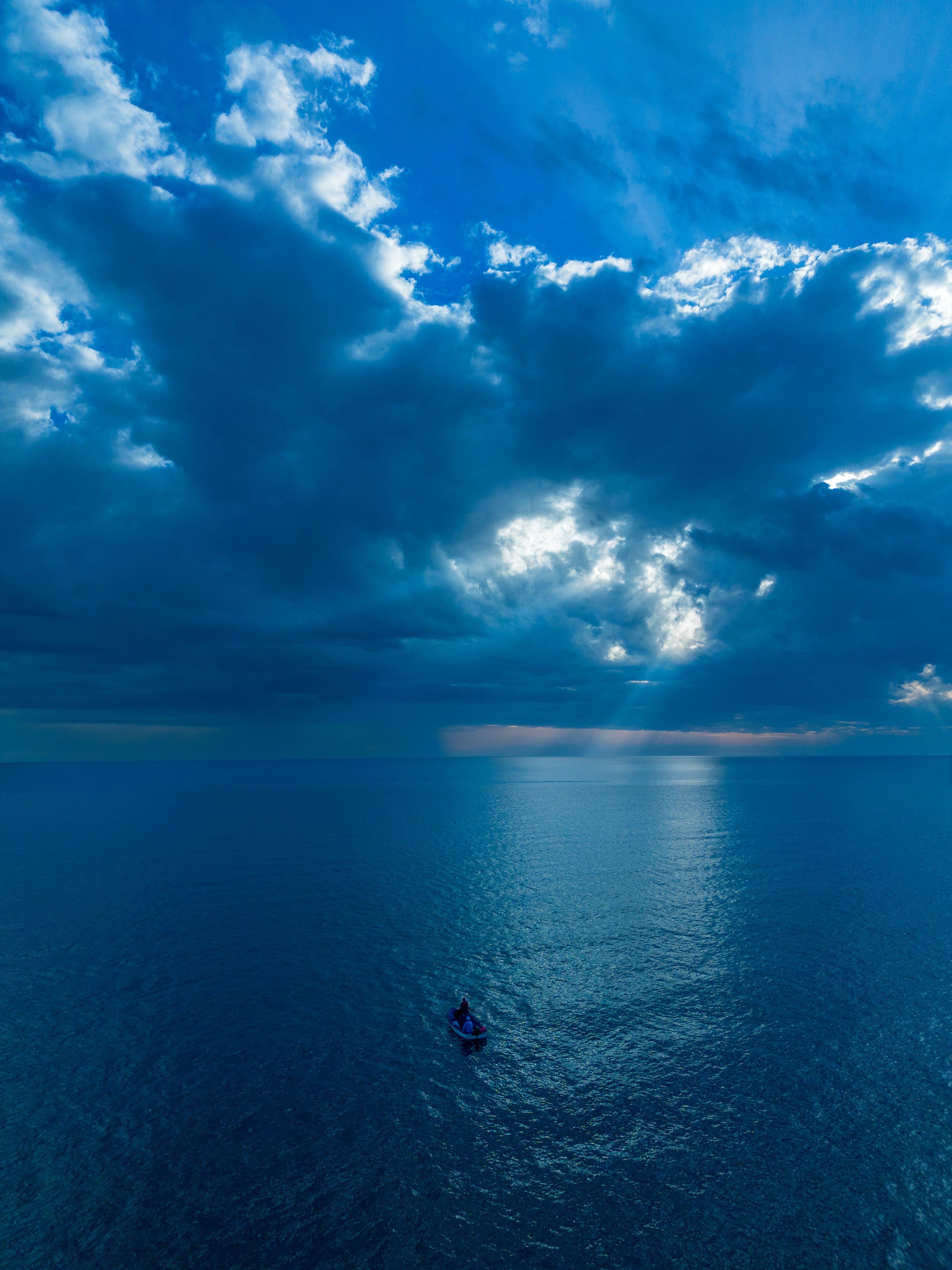 Lone Vessel Drifting Under a Break in the Cloud-Scape