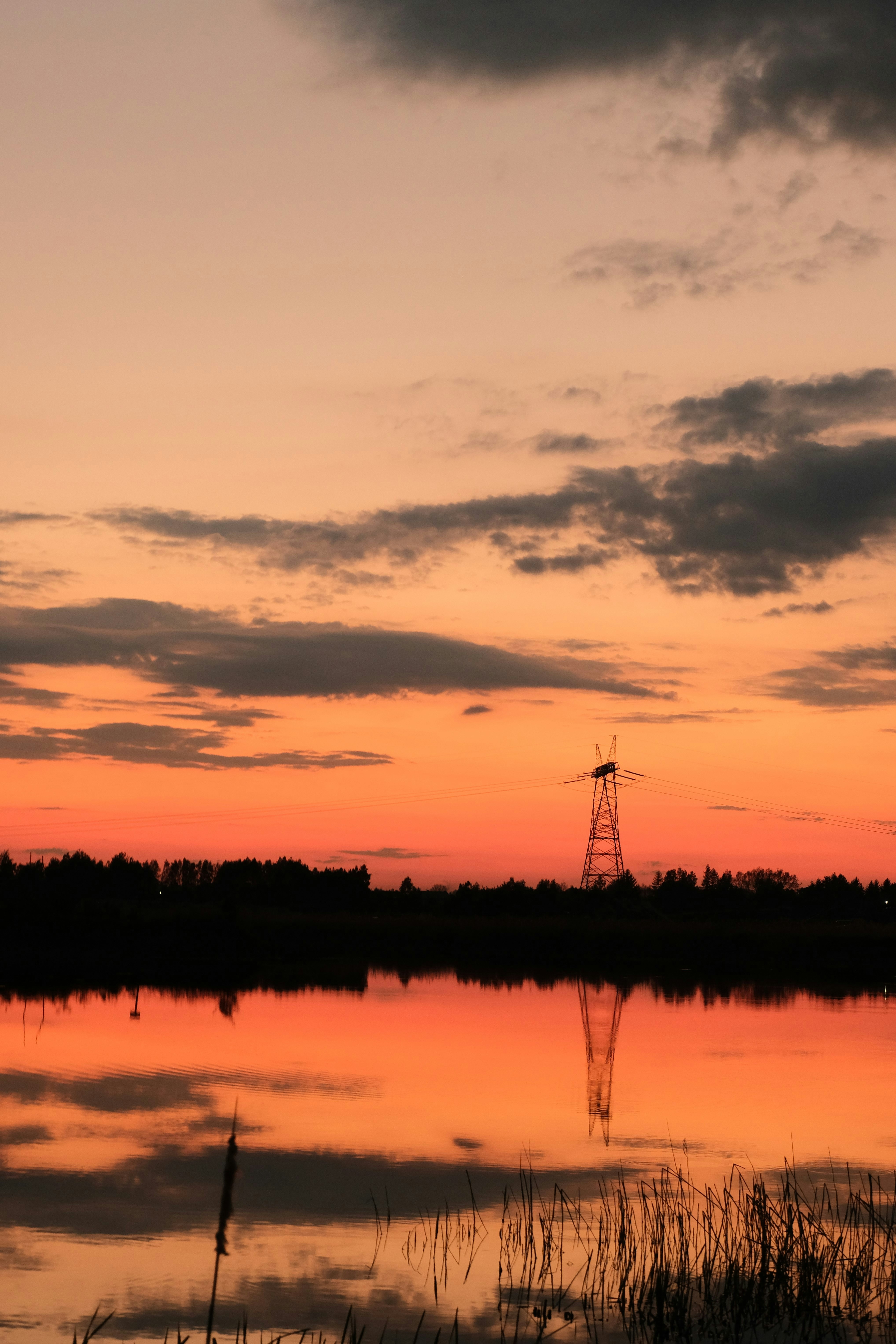 Crimson Dusk Over a Quiet Lake: The Silent Pylon Silhouetted Against Reflections