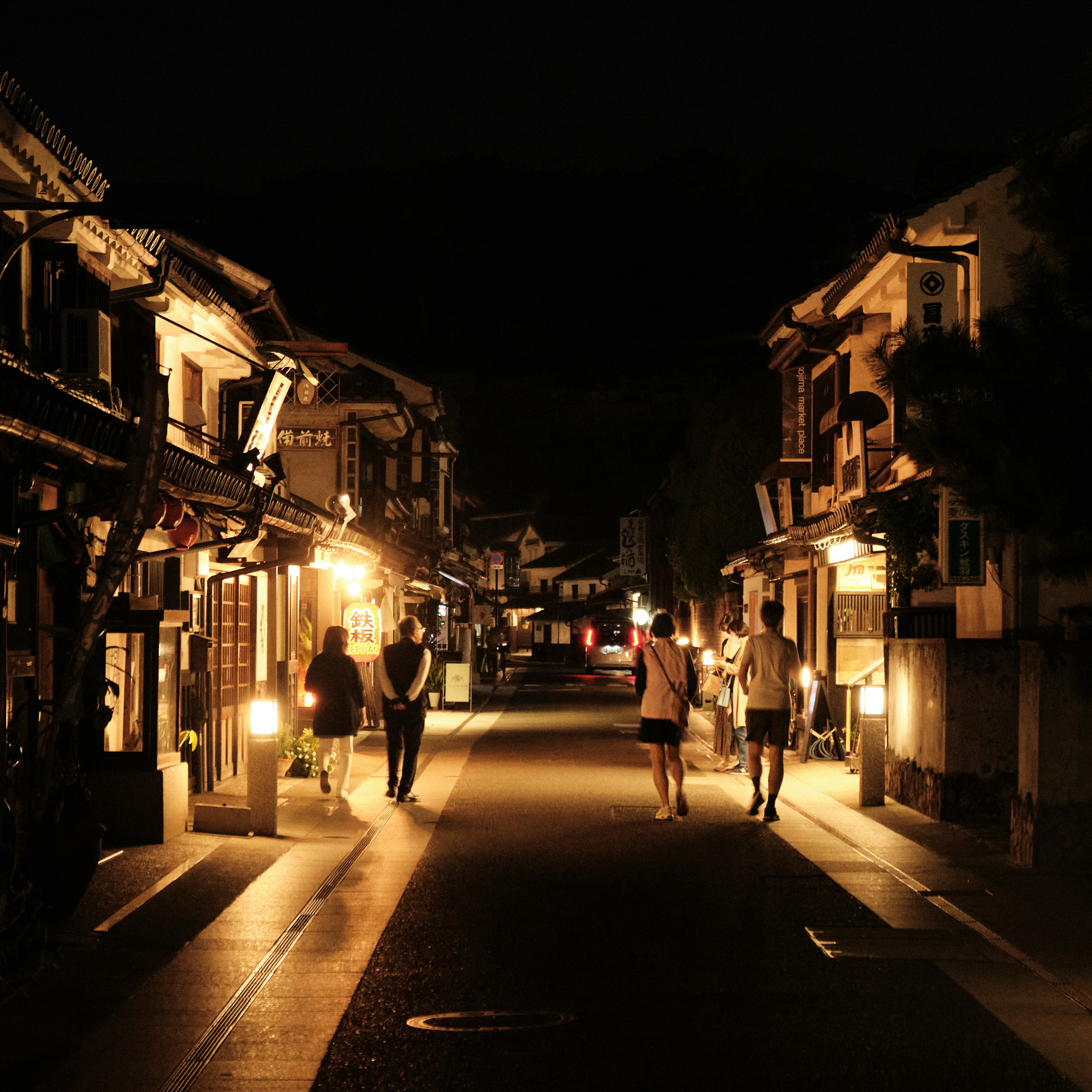 A group of people walking down a street at night photo – Free Kurashiki ...