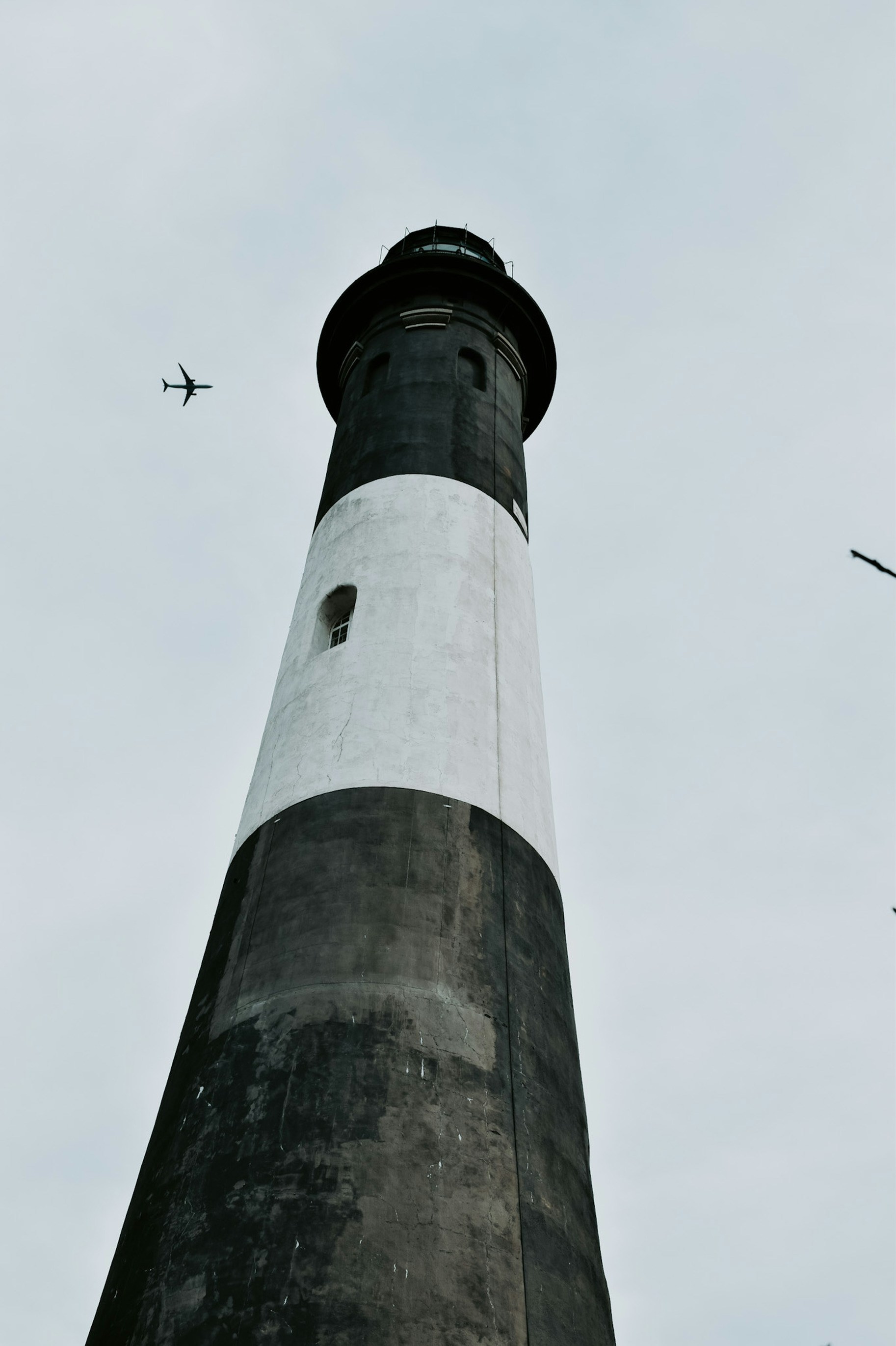 A black and white lighthouse with a plane flying by photo – Free Animal ...