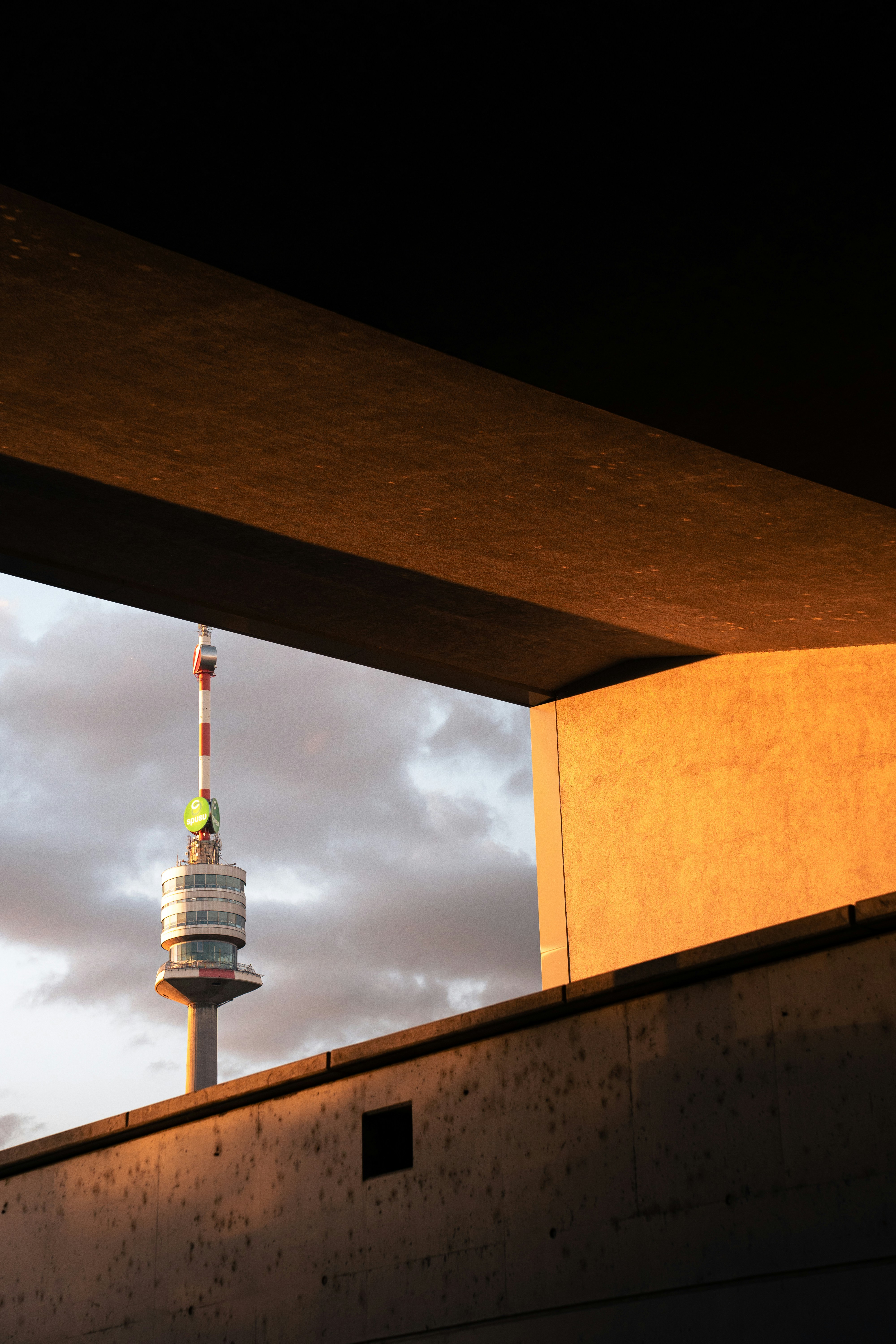 Golden Angles: A Tower Pierces Sunlit Concrete Between Urban Slabs