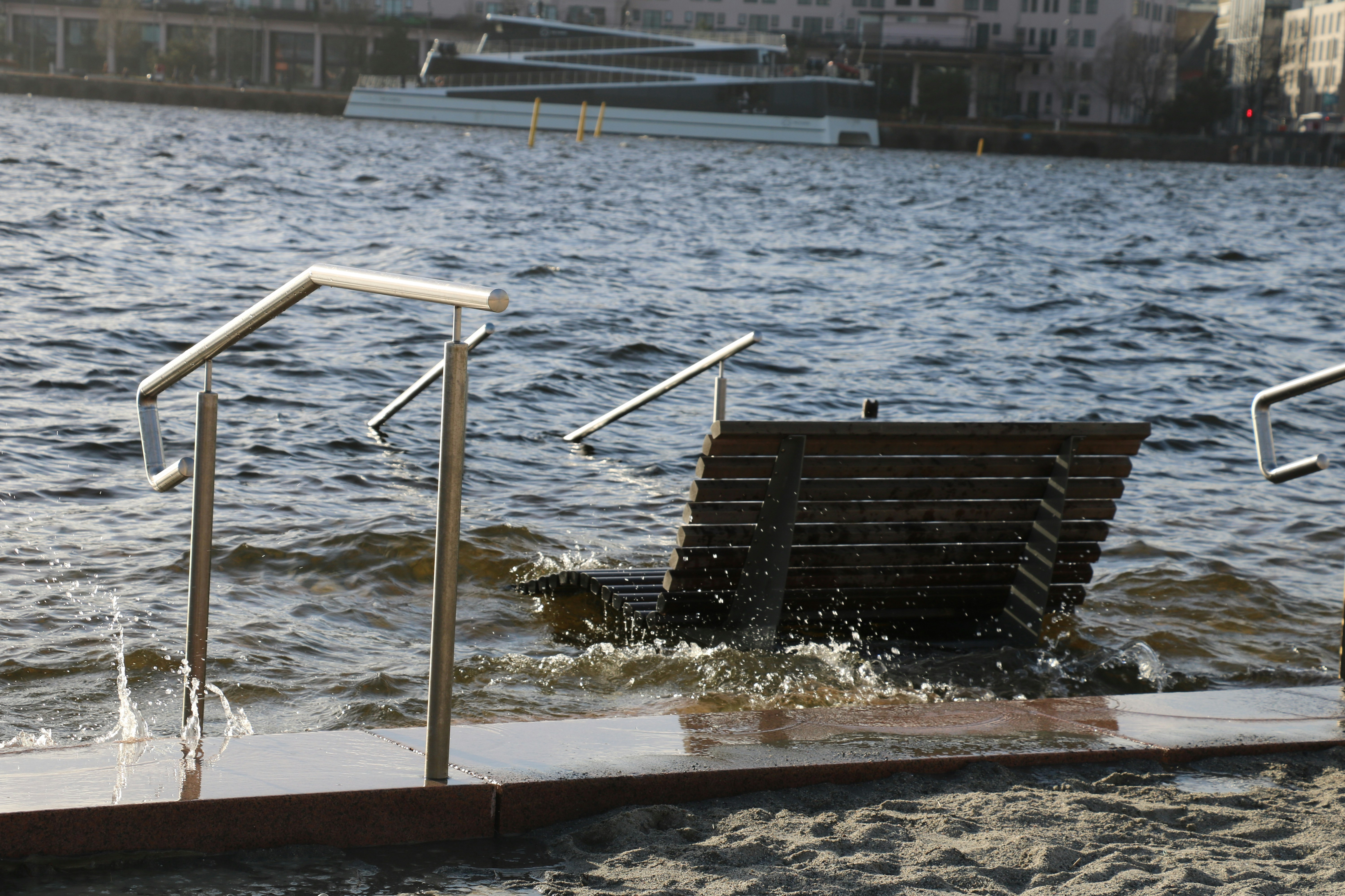 Water's Hidden Seat: A Bench Submerged Along the Riverside Promenade