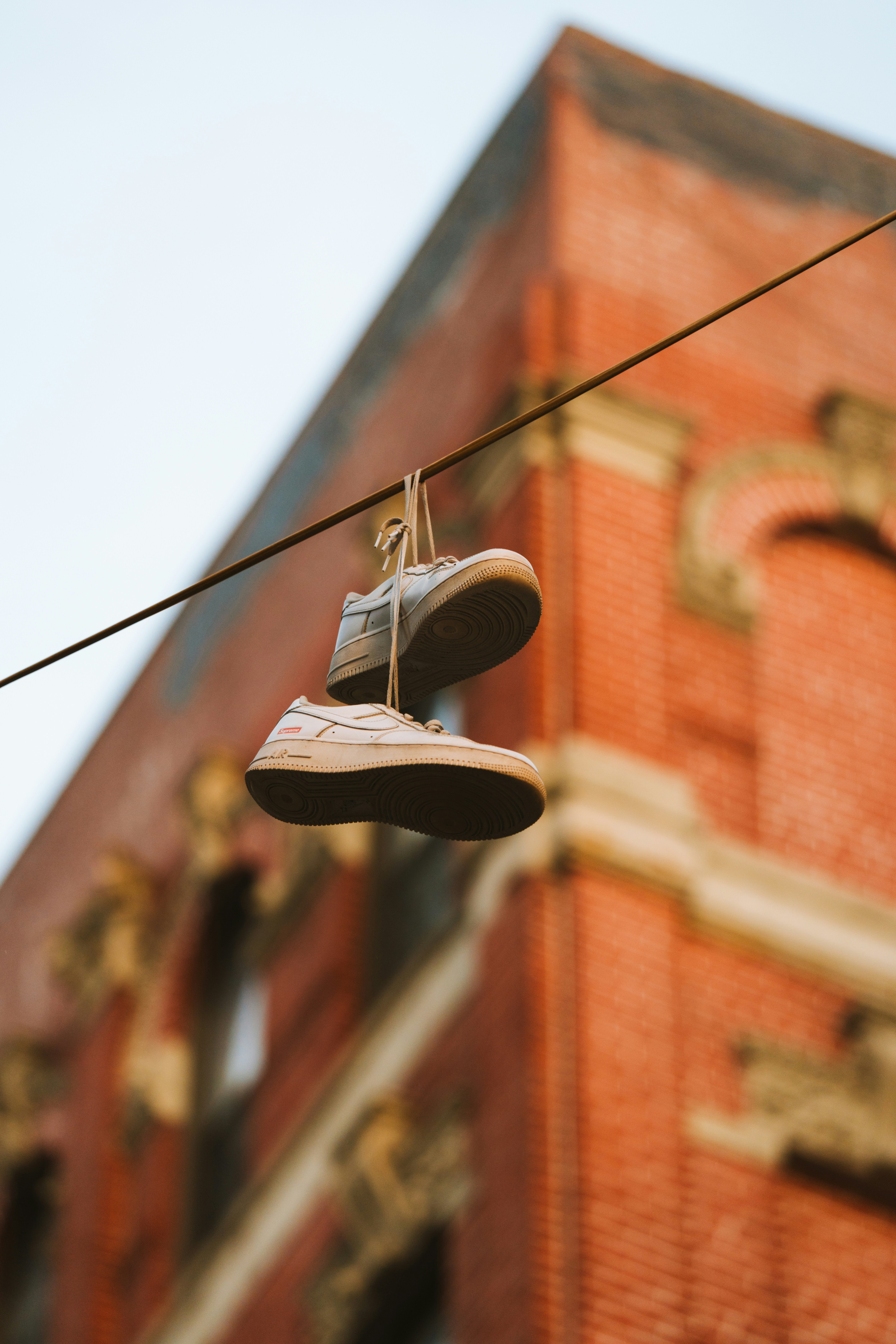 Suspended Sneakers Over a Red Brick Facade