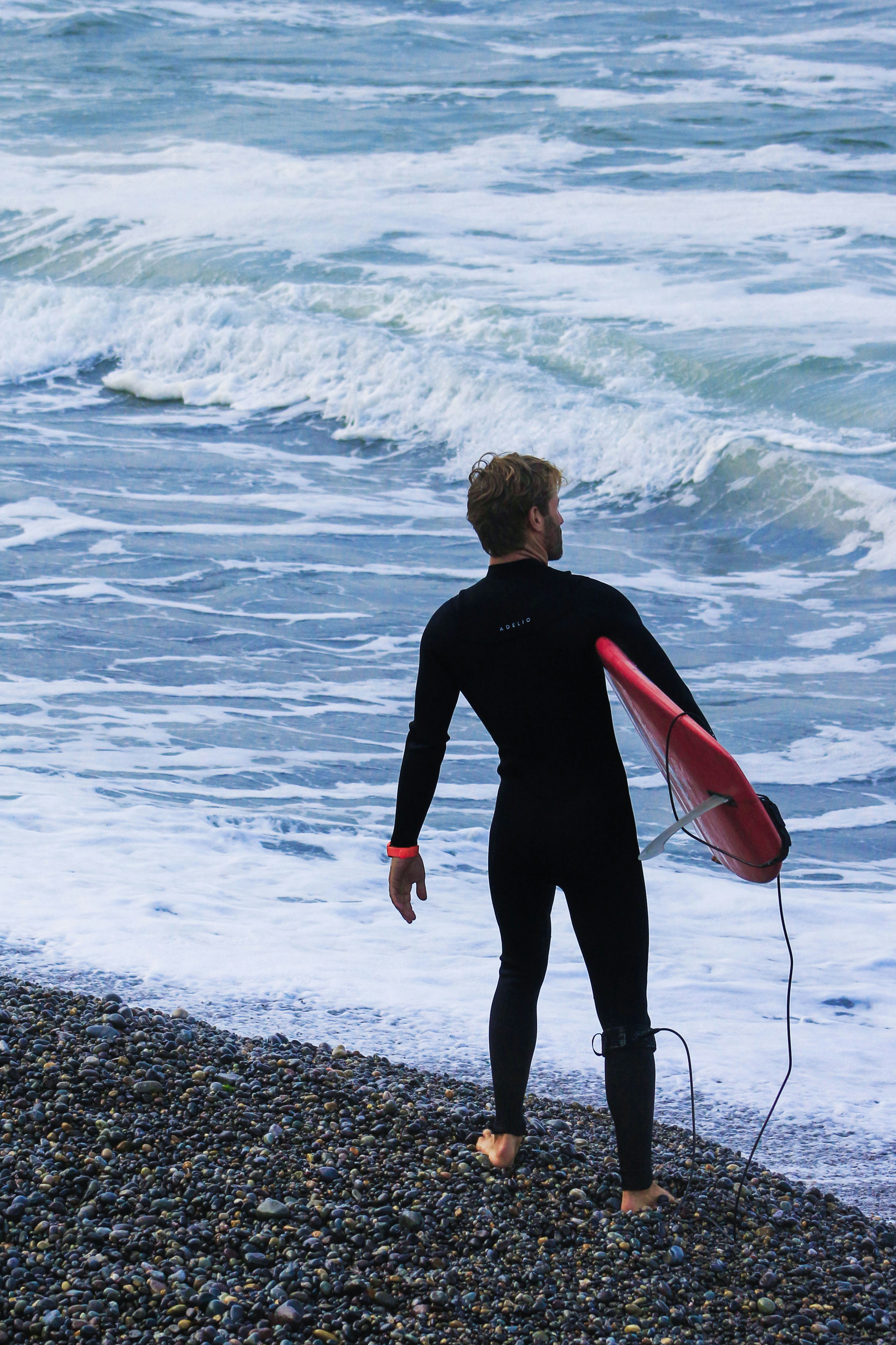 Pebble Beach Surfer: a lone rider with a red board faces the rolling Atlantic