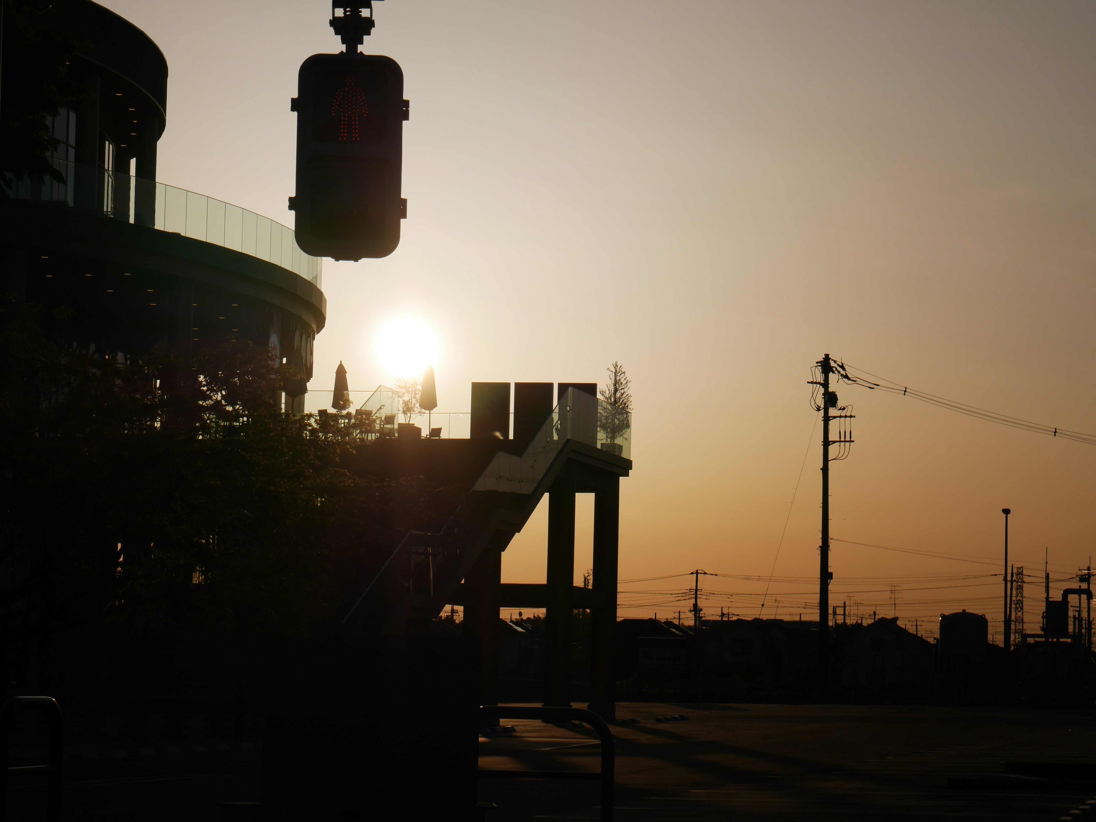 The sun is setting behind a building with a traffic light photo – Free ...