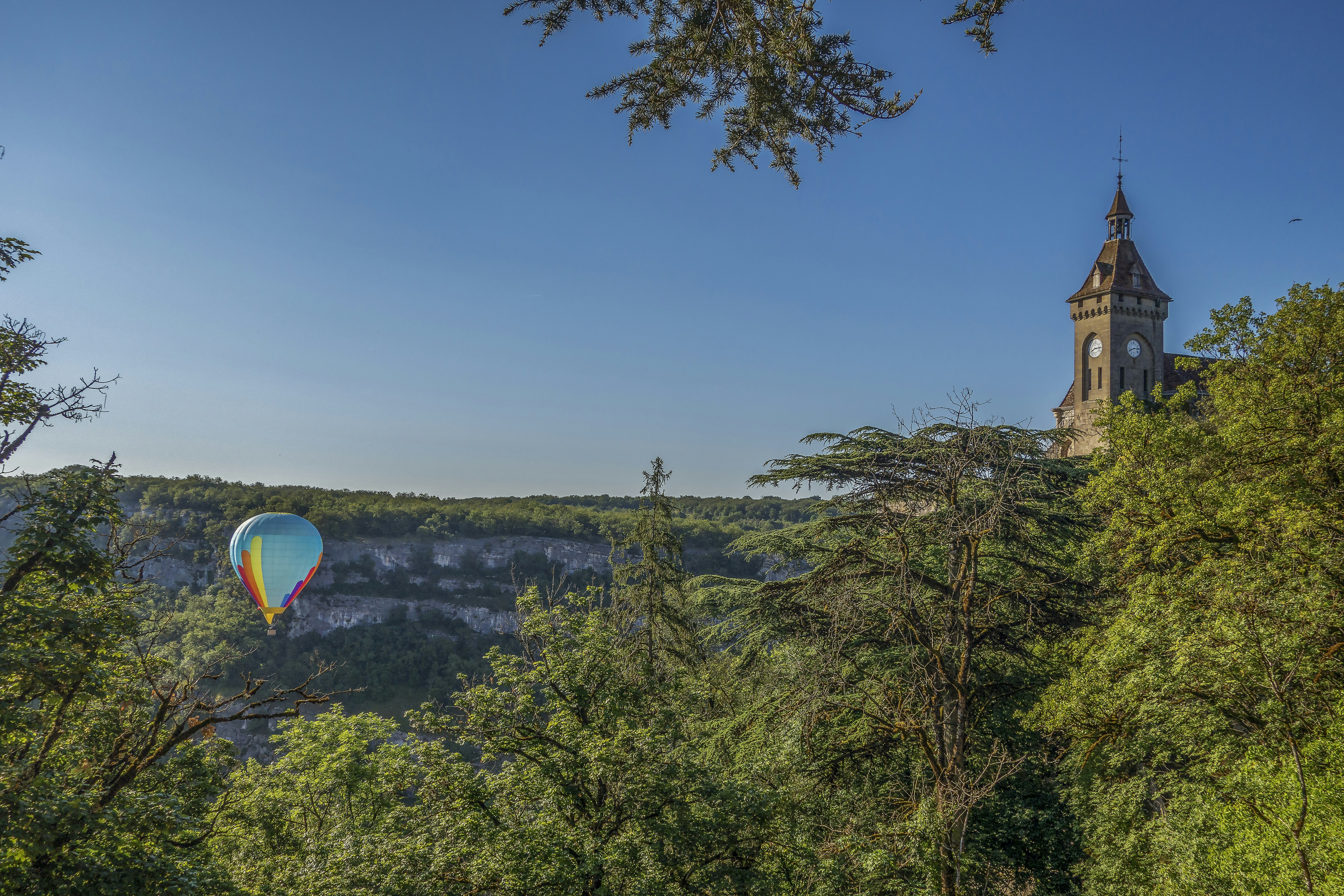 Hot Air, Quiet Hill: Balloon over a Sunlit Forest and Clocktower
