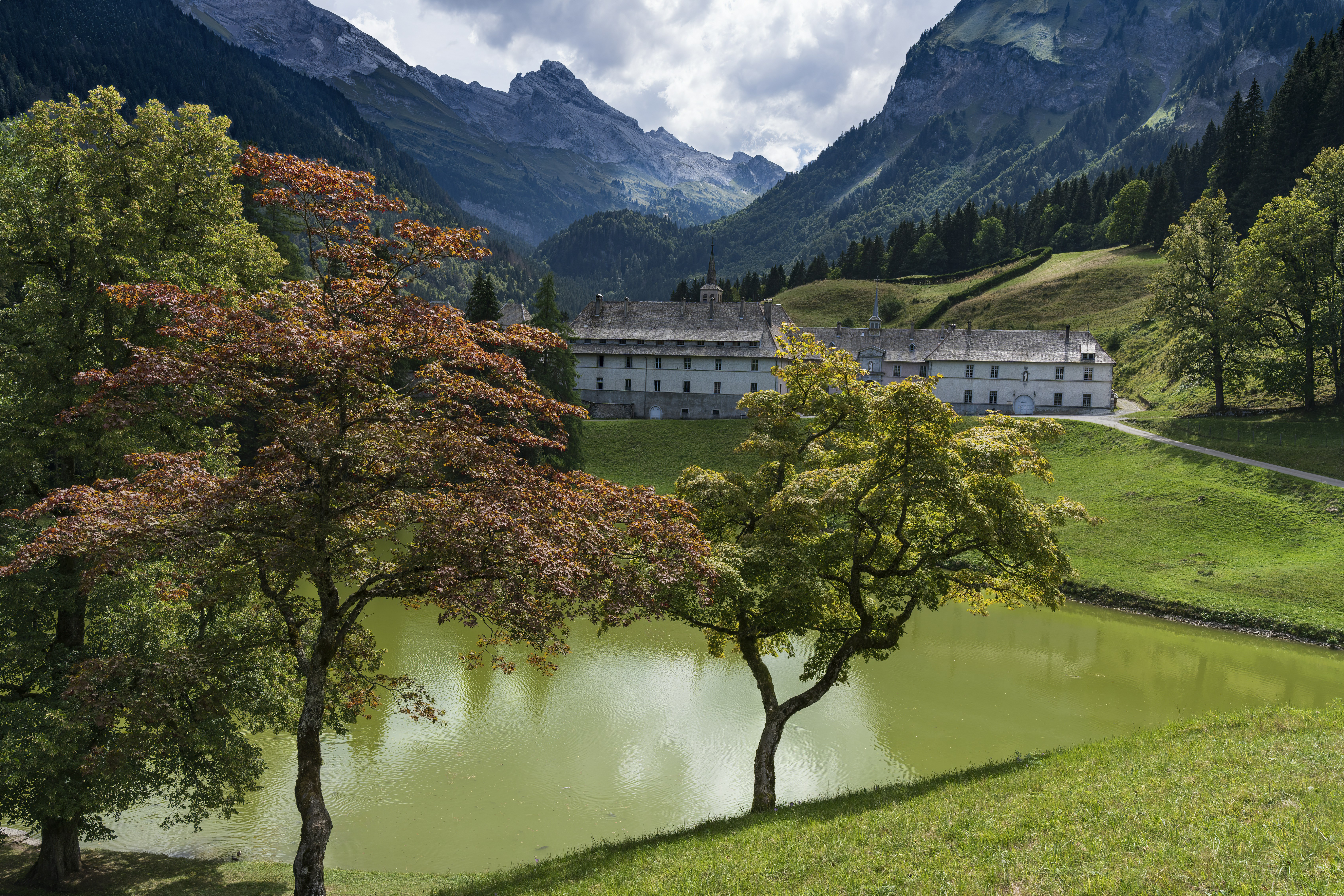 Alpine Manor Beside a Verdant Lake Under Distant Peaks