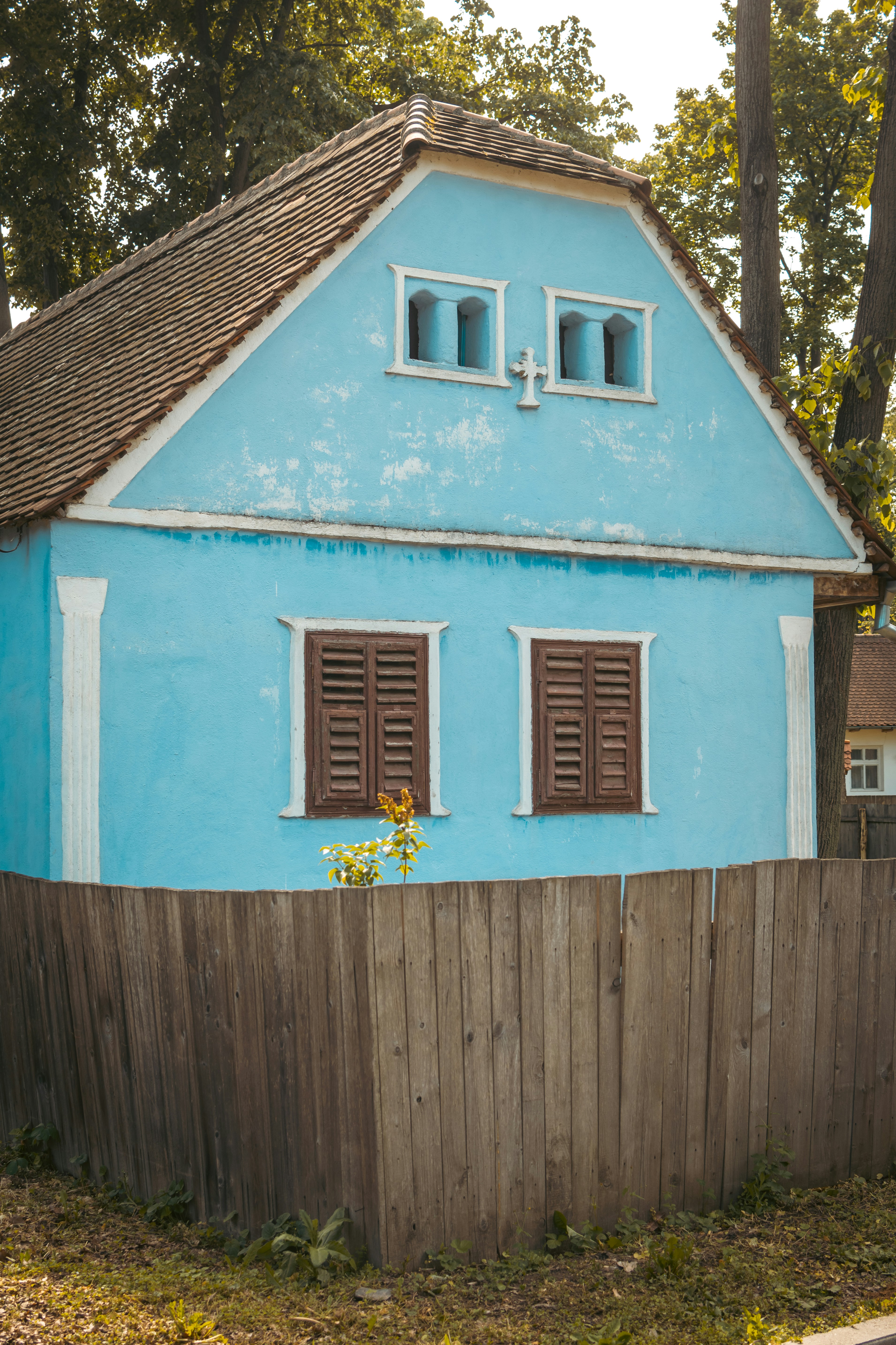 Azure Cottage Framed by a Weathered Fence