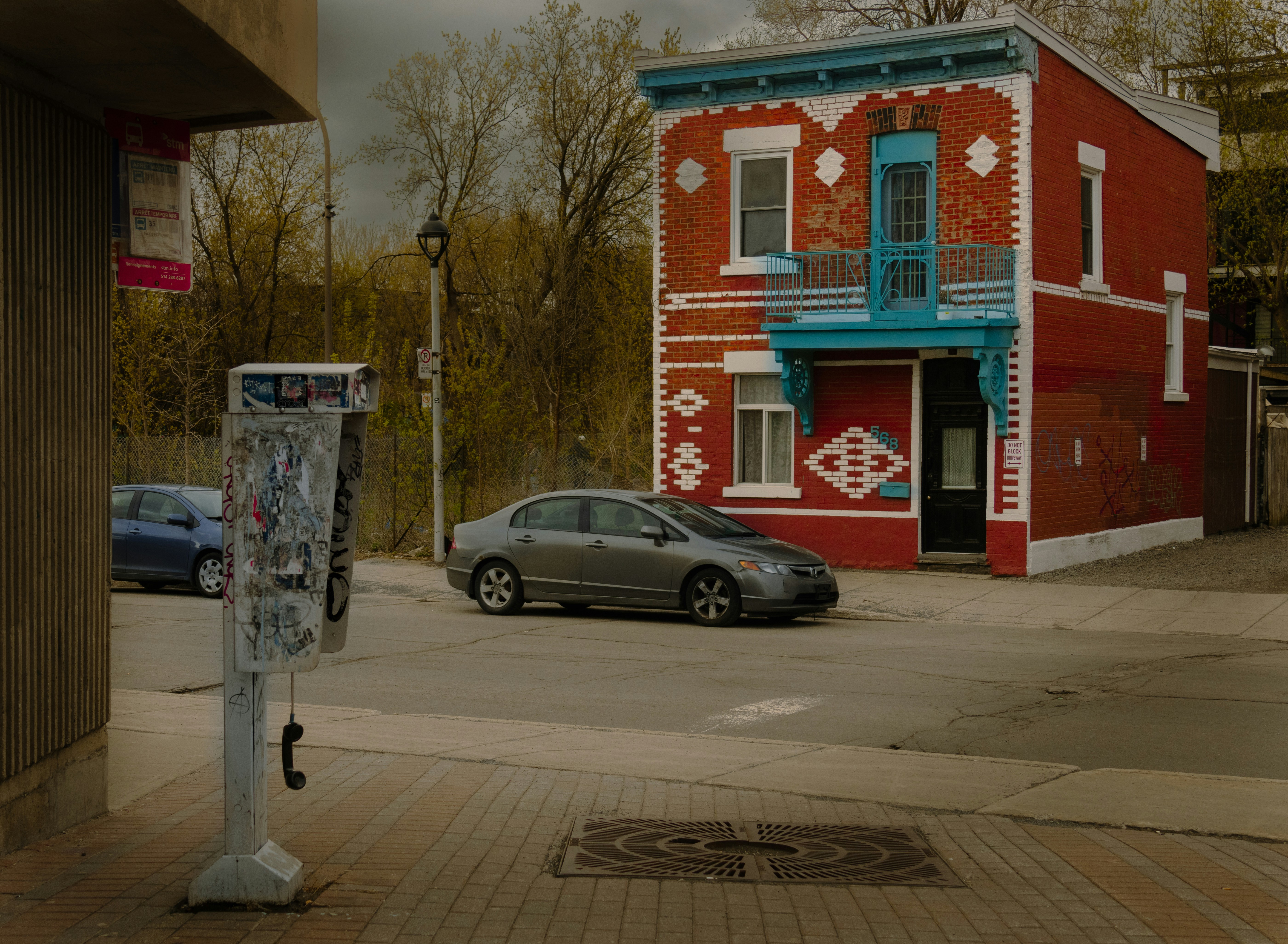 Vibrantly painted brick building at a city intersection, showcasing unique architectural details and a vintage payphone nearby.