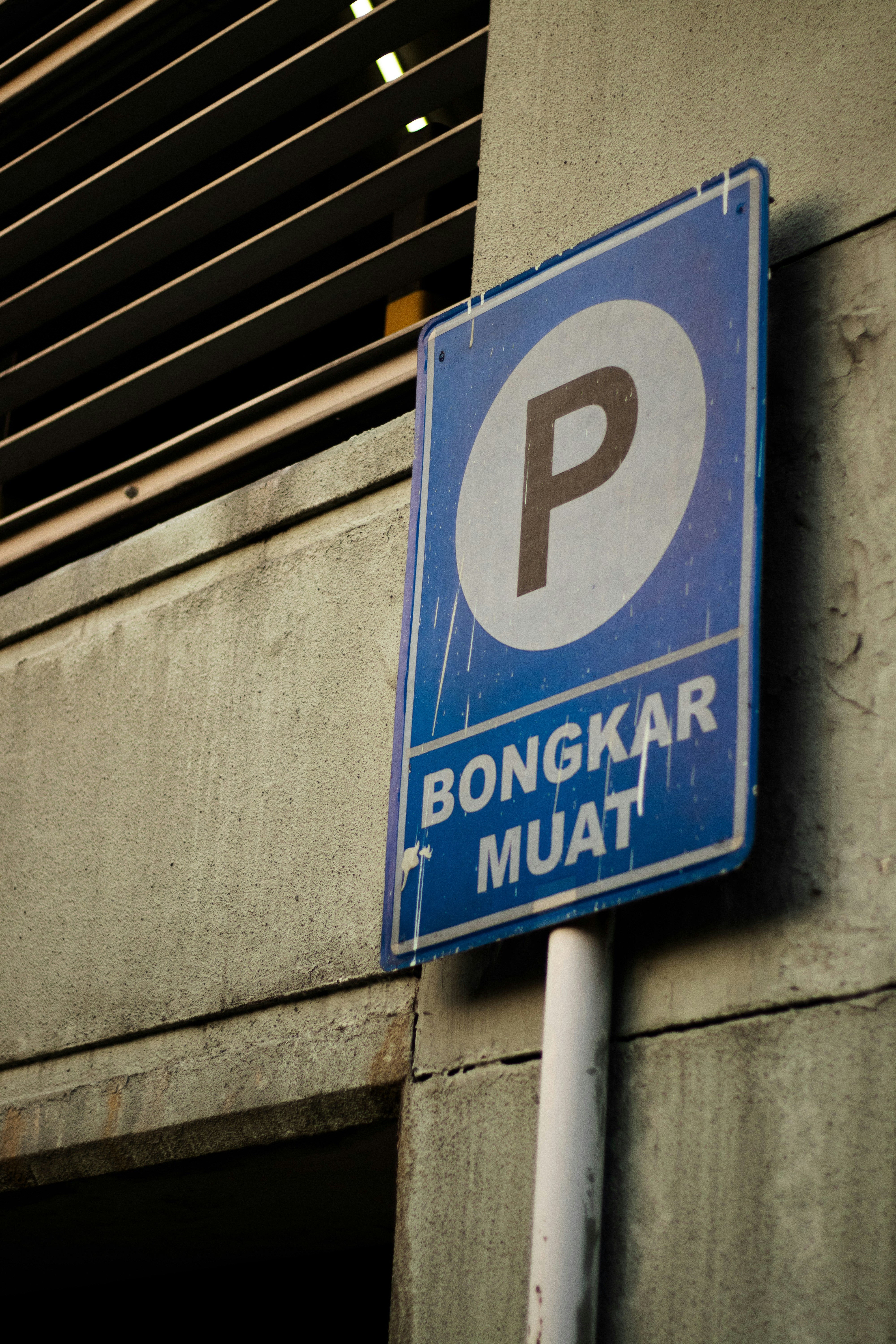 Weathered Blue Parking Sign Clinging to a Concrete Facade