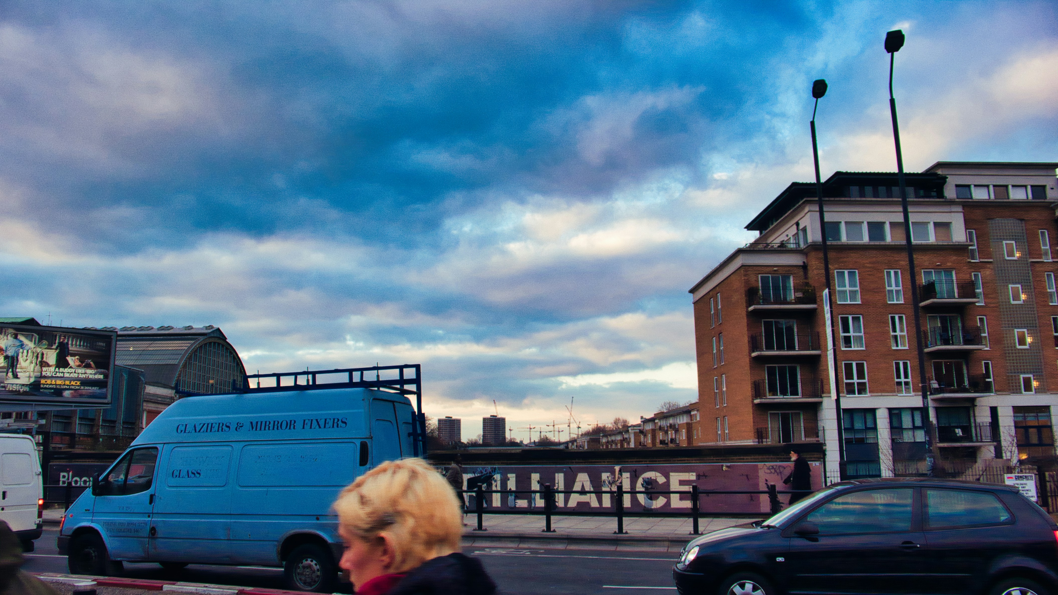 A blue van driving down a street next to tall buildings photo – Free ...