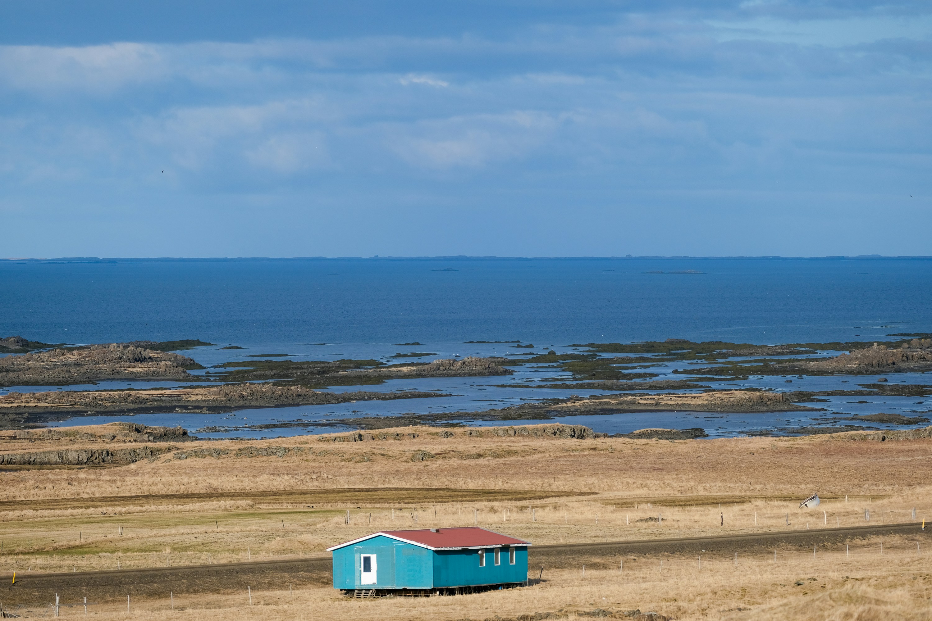A small blue building sitting in a field next to a body of water photo ...