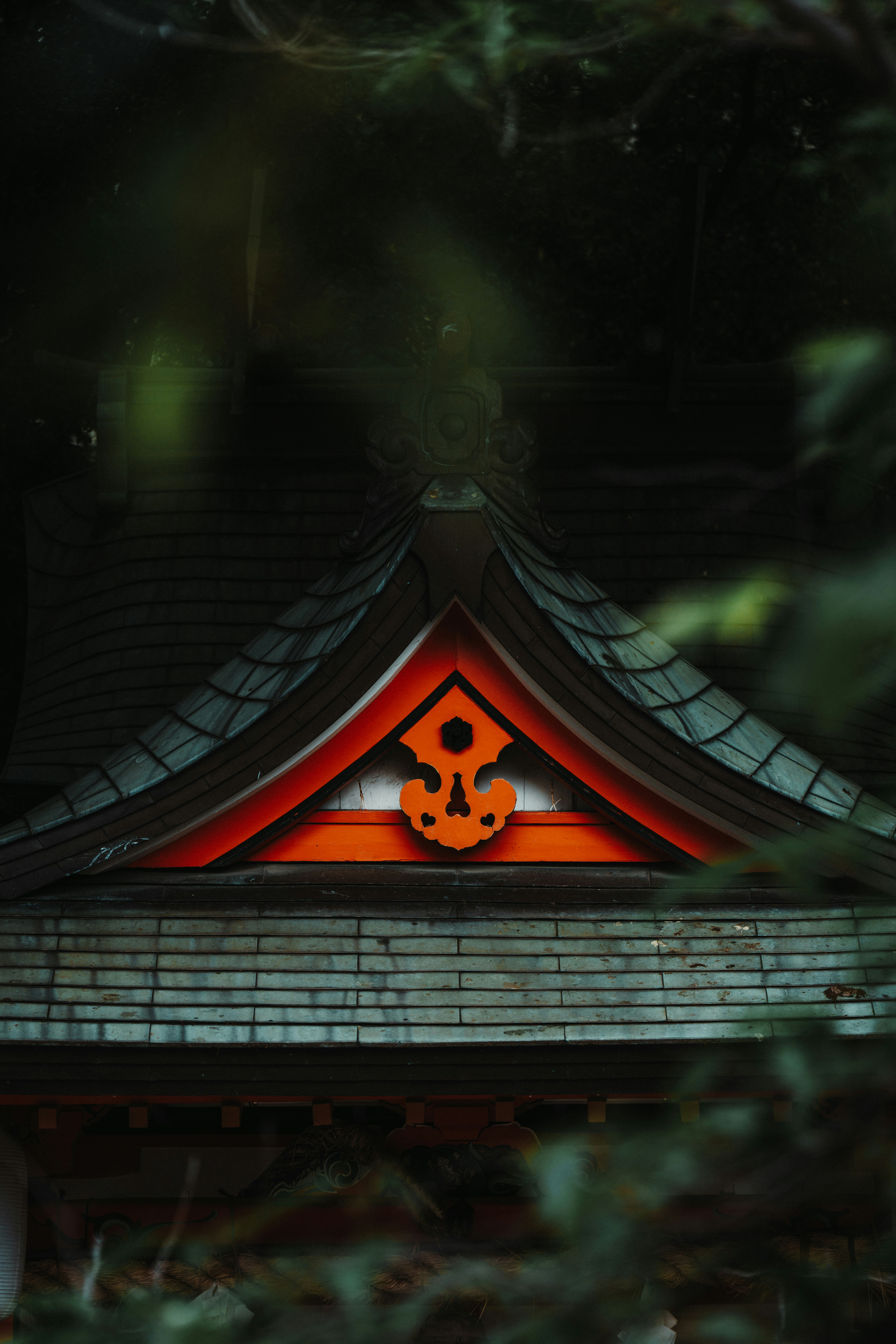 Amber crest on a temple roof framed by blurred greenery