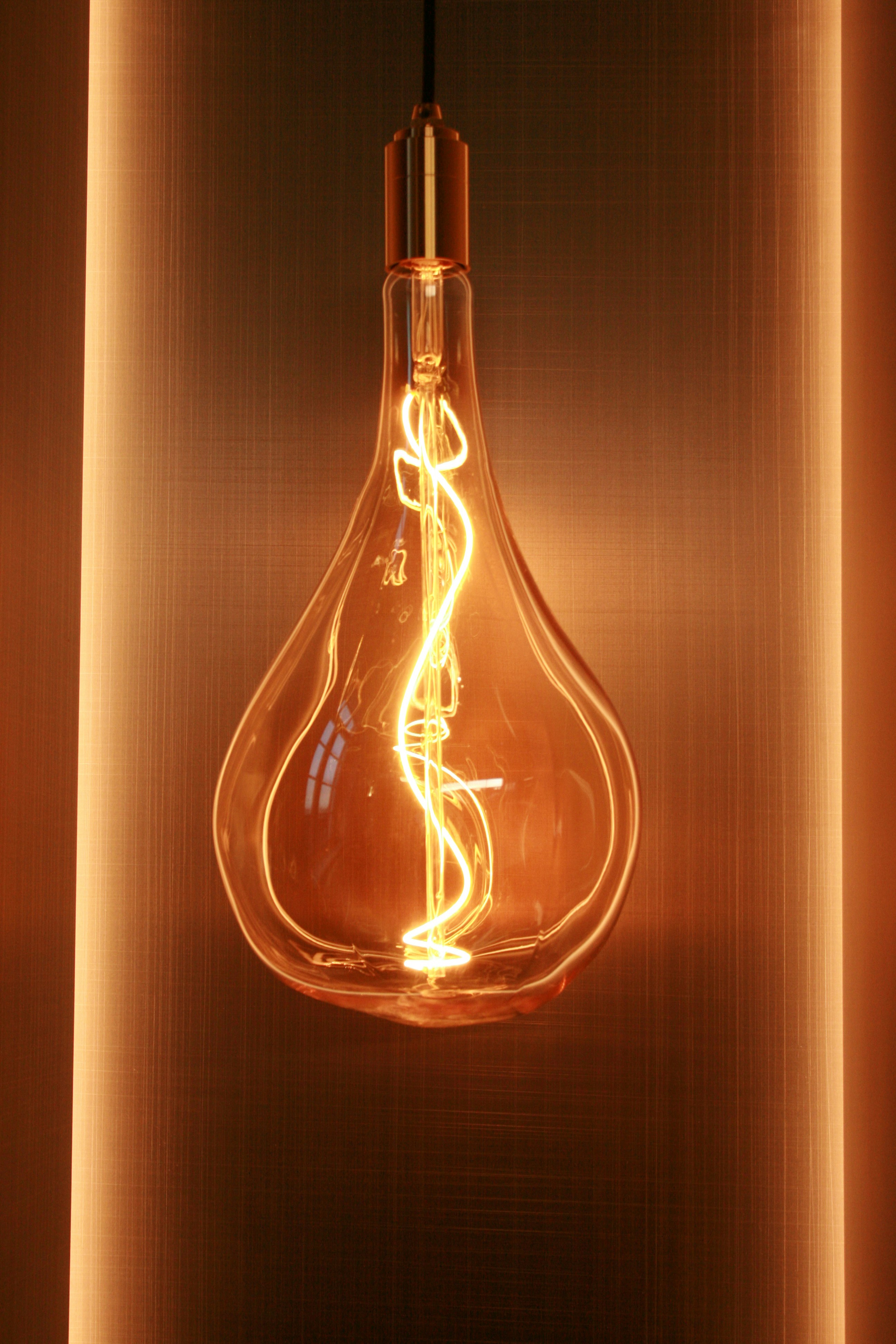 Vintage light bulb with a glowing filament, suspended against a softly lit backdrop. The warm tones create a cozy atmosphere.