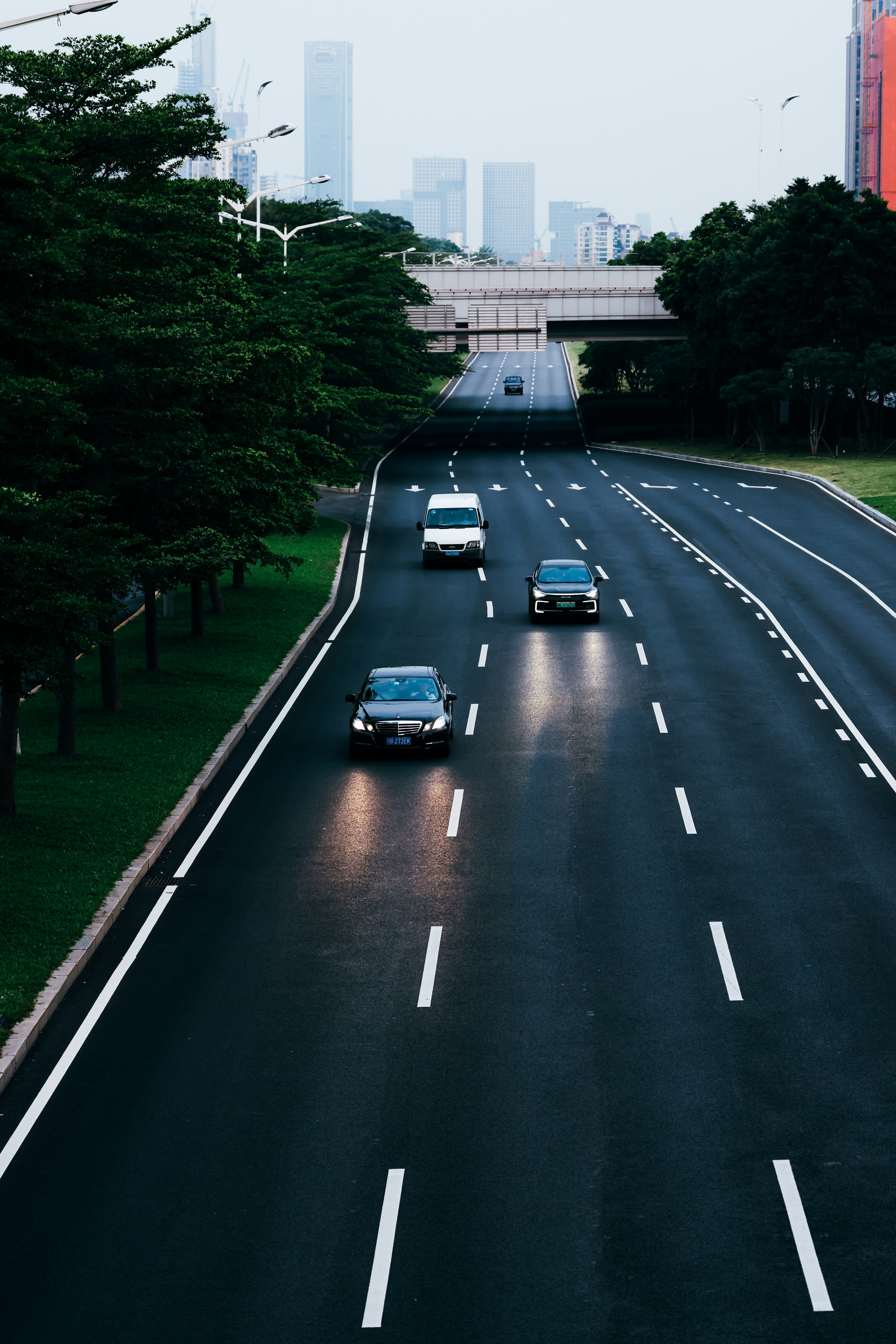 Two cars driving down a highway with a bridge in the background photo ...