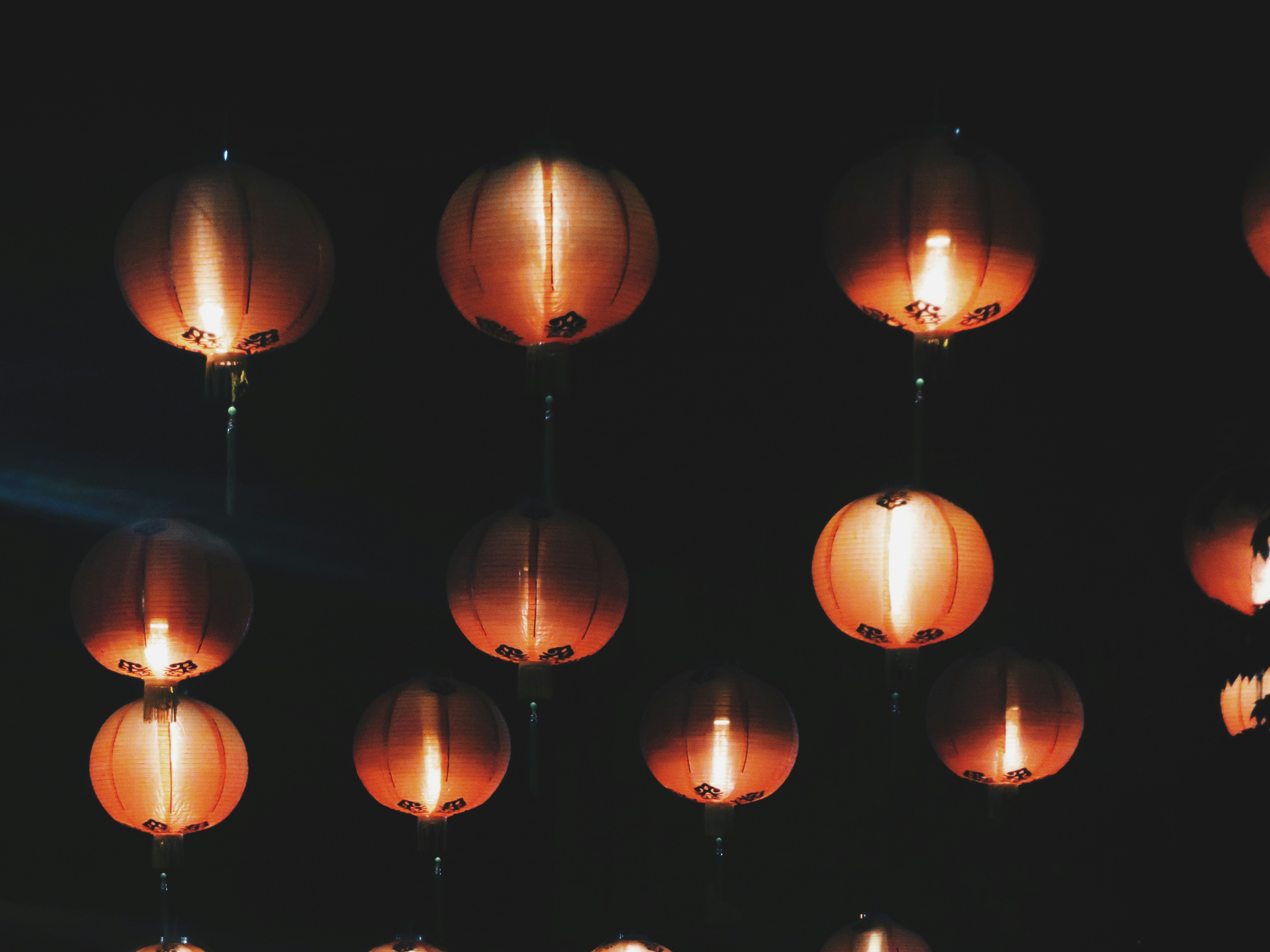 Rows of glowing lanterns suspended against a dark backdrop.