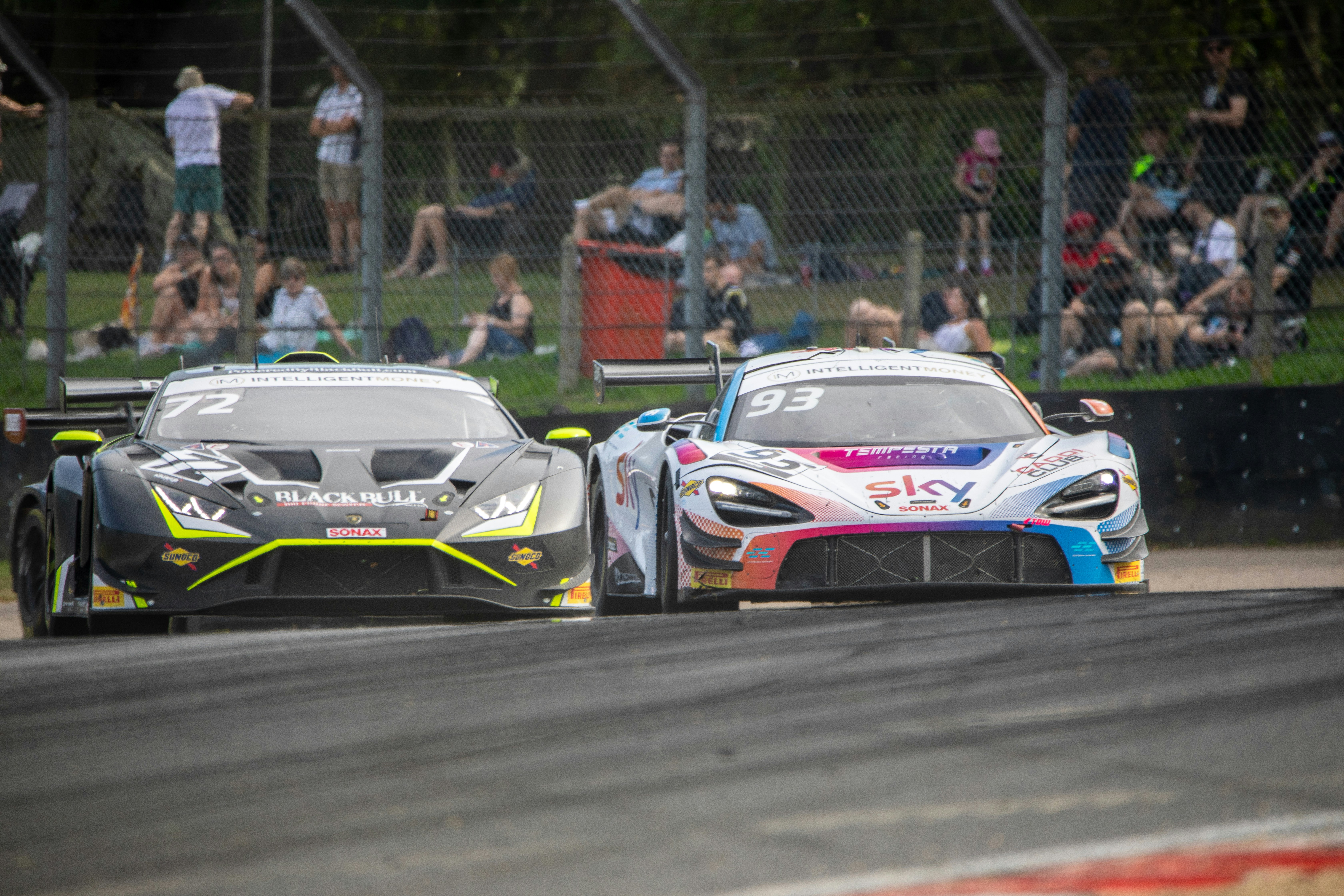 Two racing cars on a race track with spectators in the background photo ...