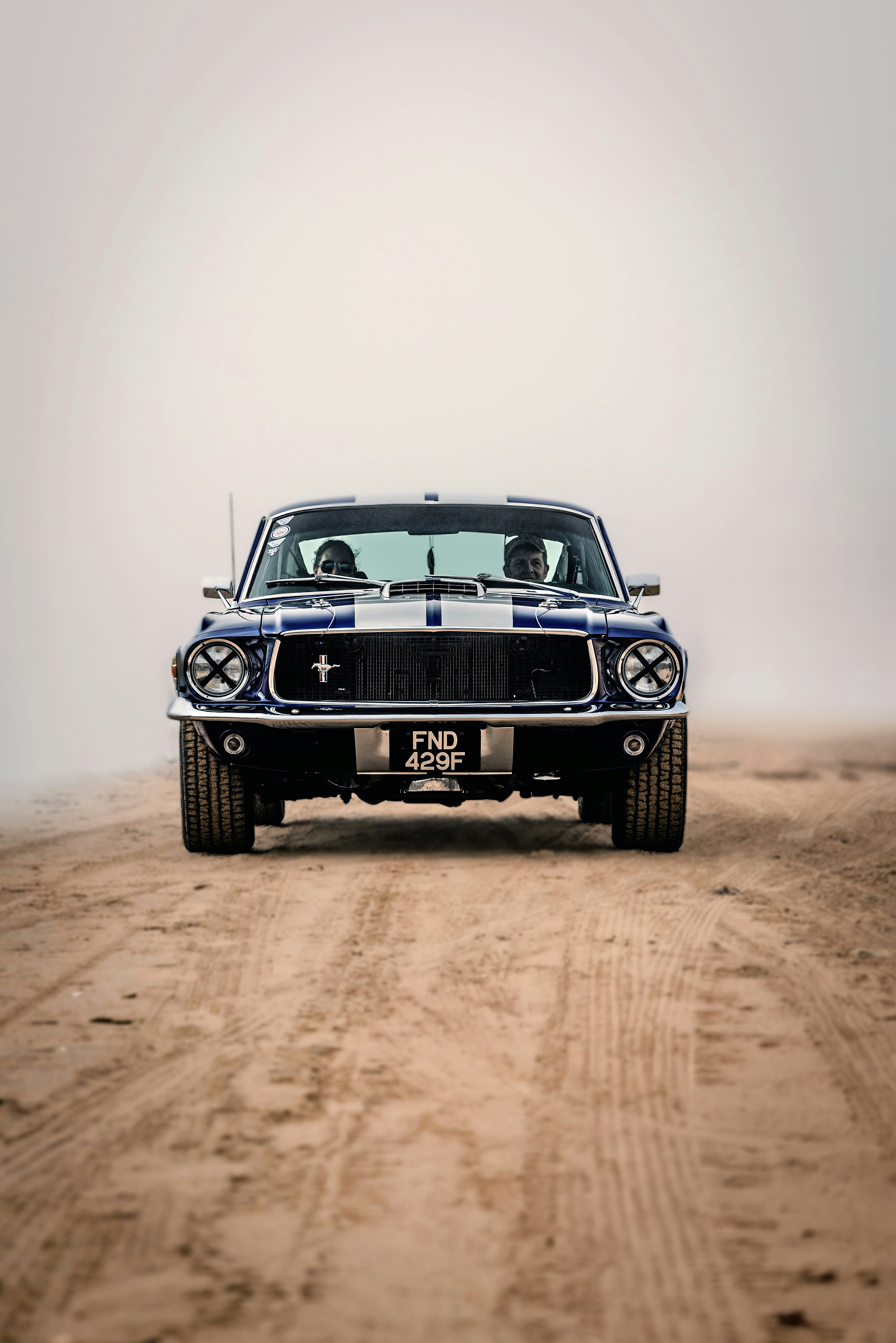 Desert Thunder: Front View of a Blue Classic Ford Mustang on a Dusty Road