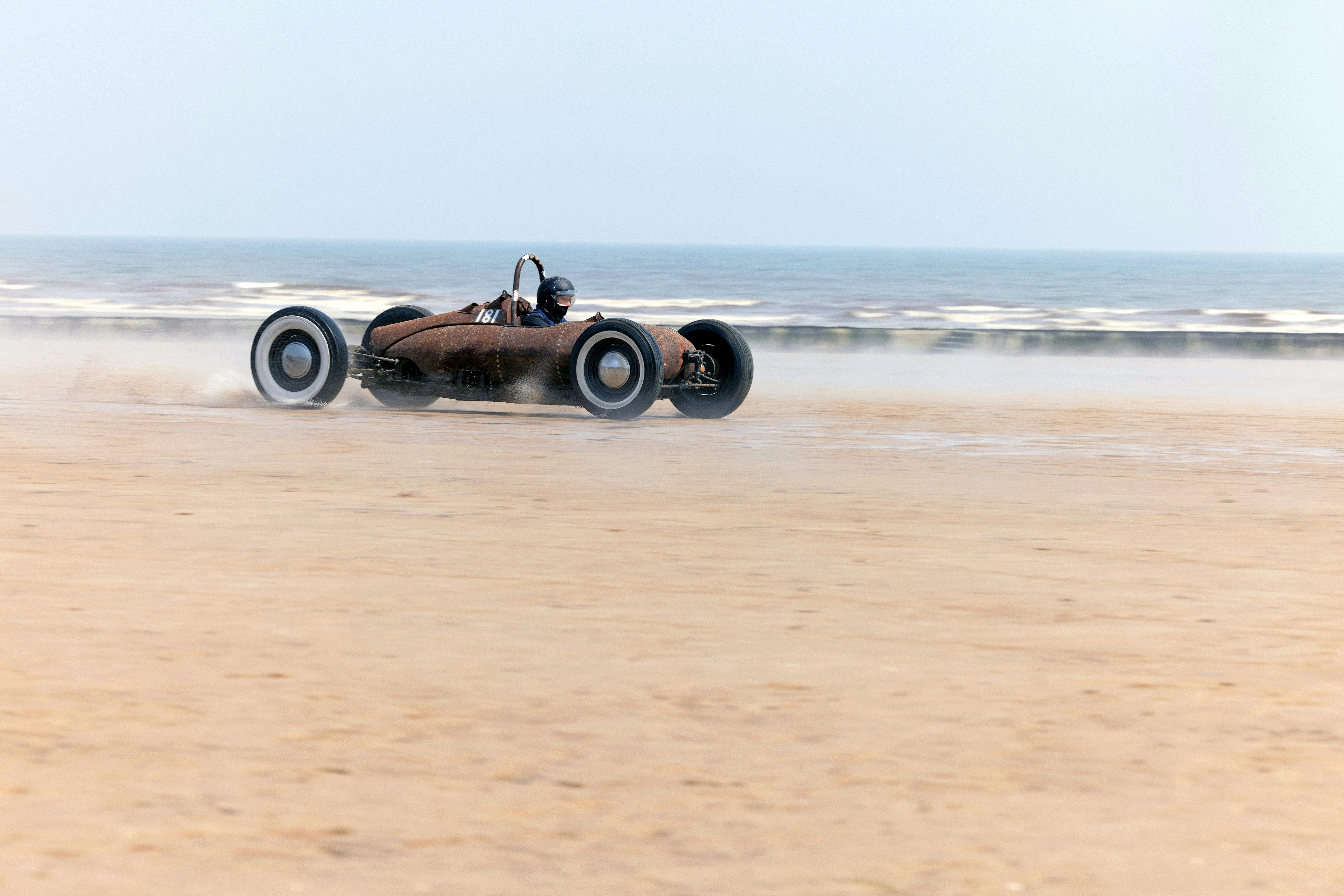 Seaside Sprint: A vintage racer carving dust along sunlit shore