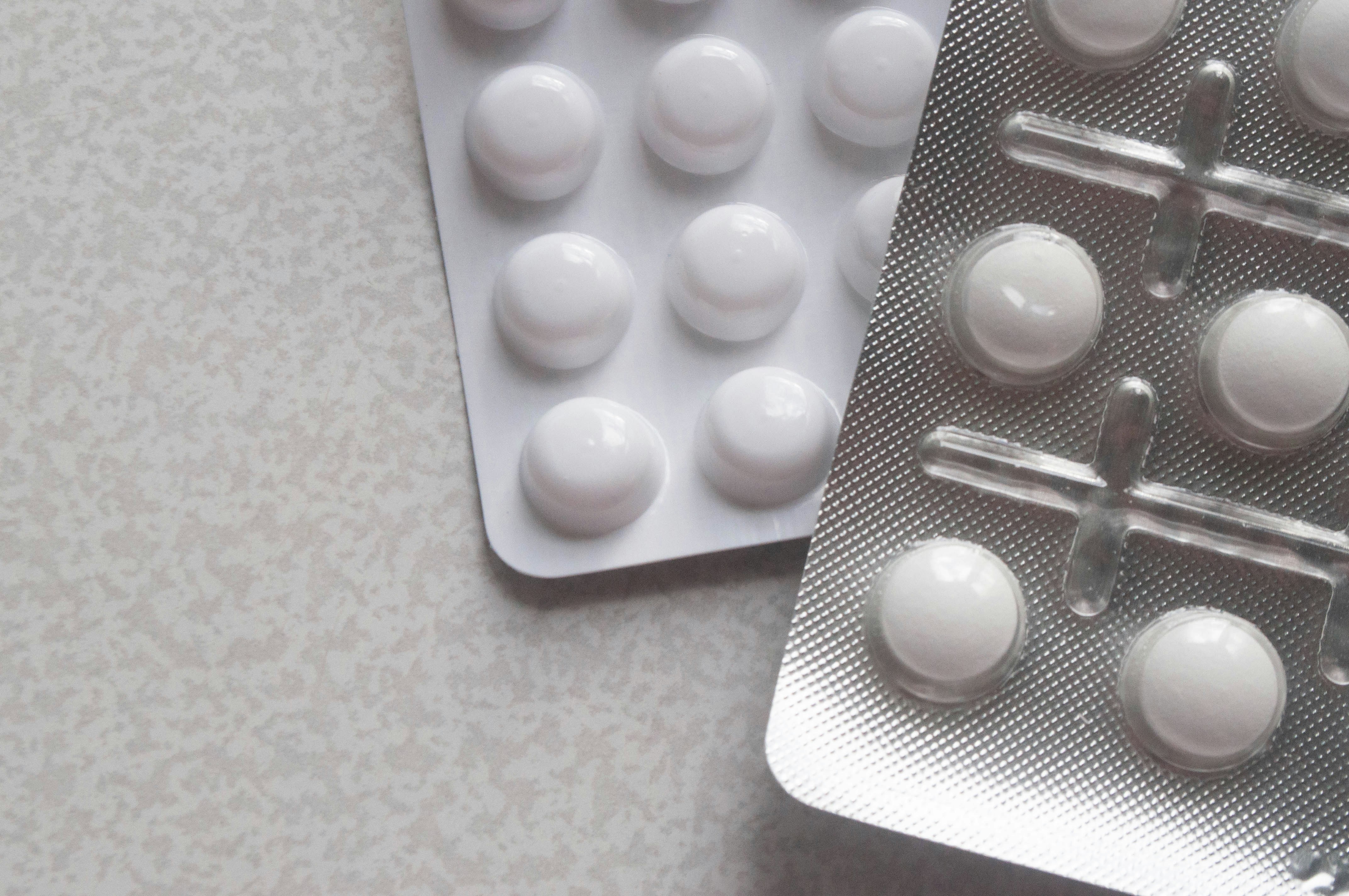 Two new blister packs of tablets on a table, top view | a pack of pills next to a contraption on a table