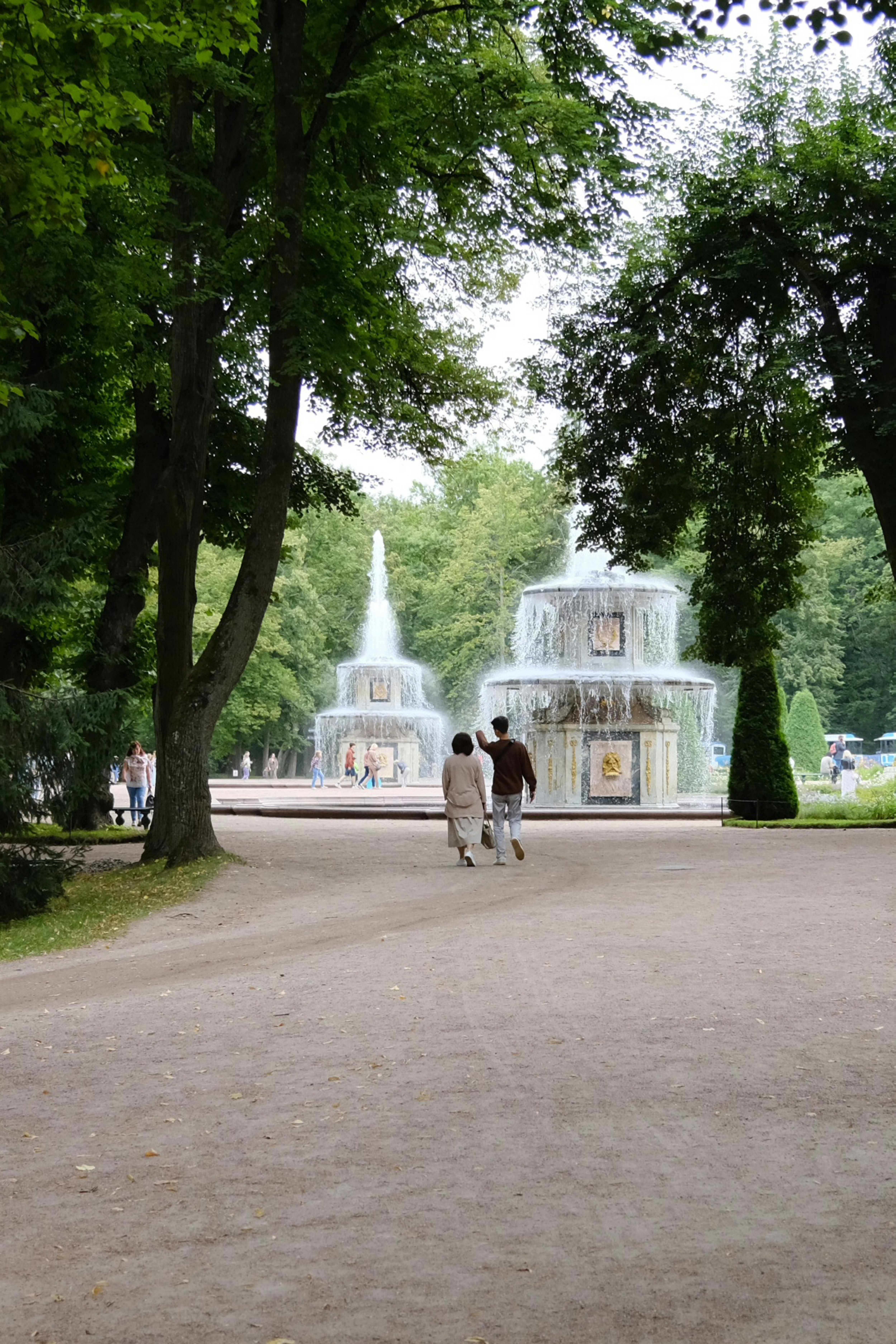 Shaded Path Toward a Tiered Fountain in a Lush Park