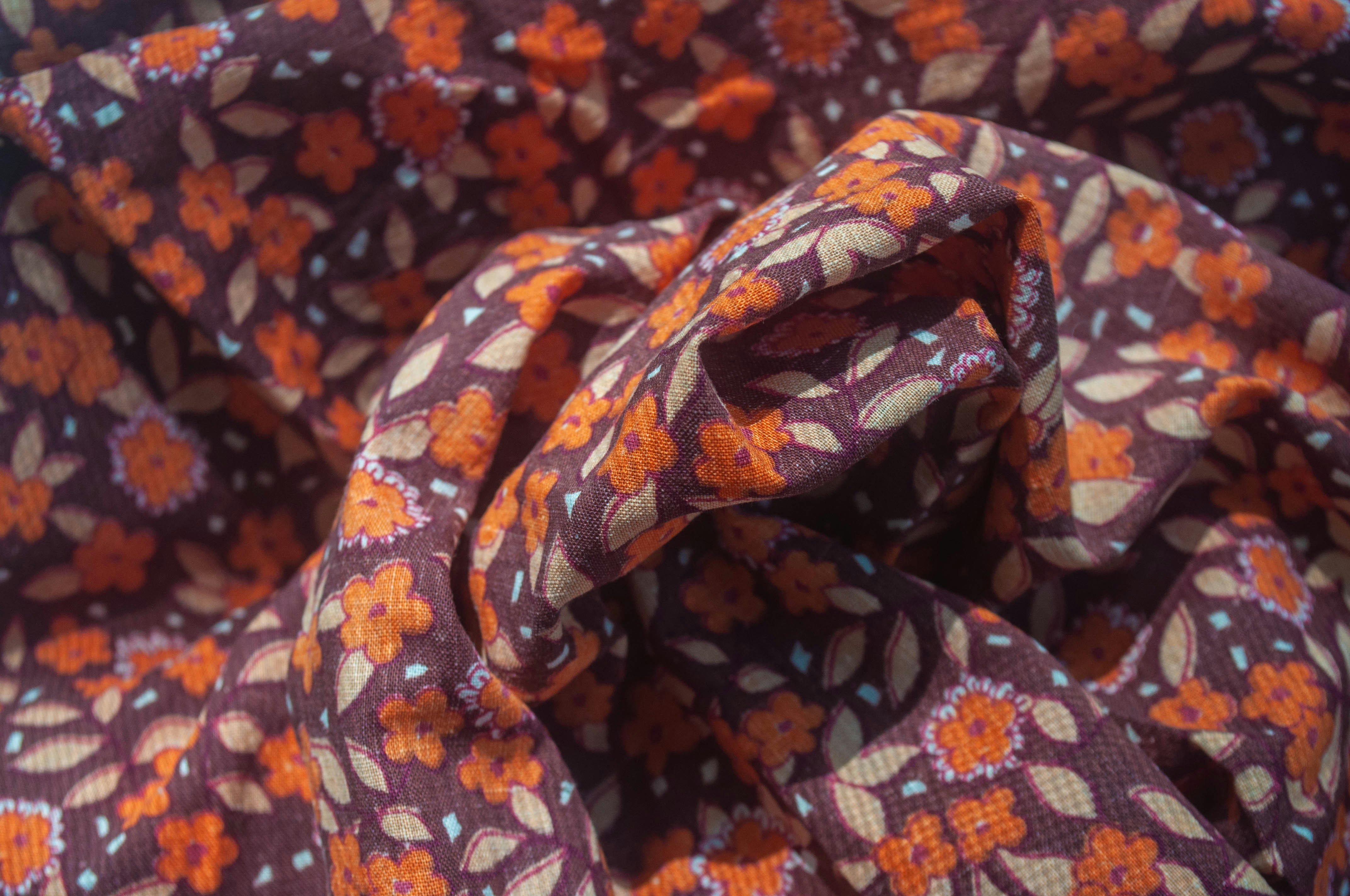 Crumpled cotton fabric with floral print in brown, orange, beige colors.