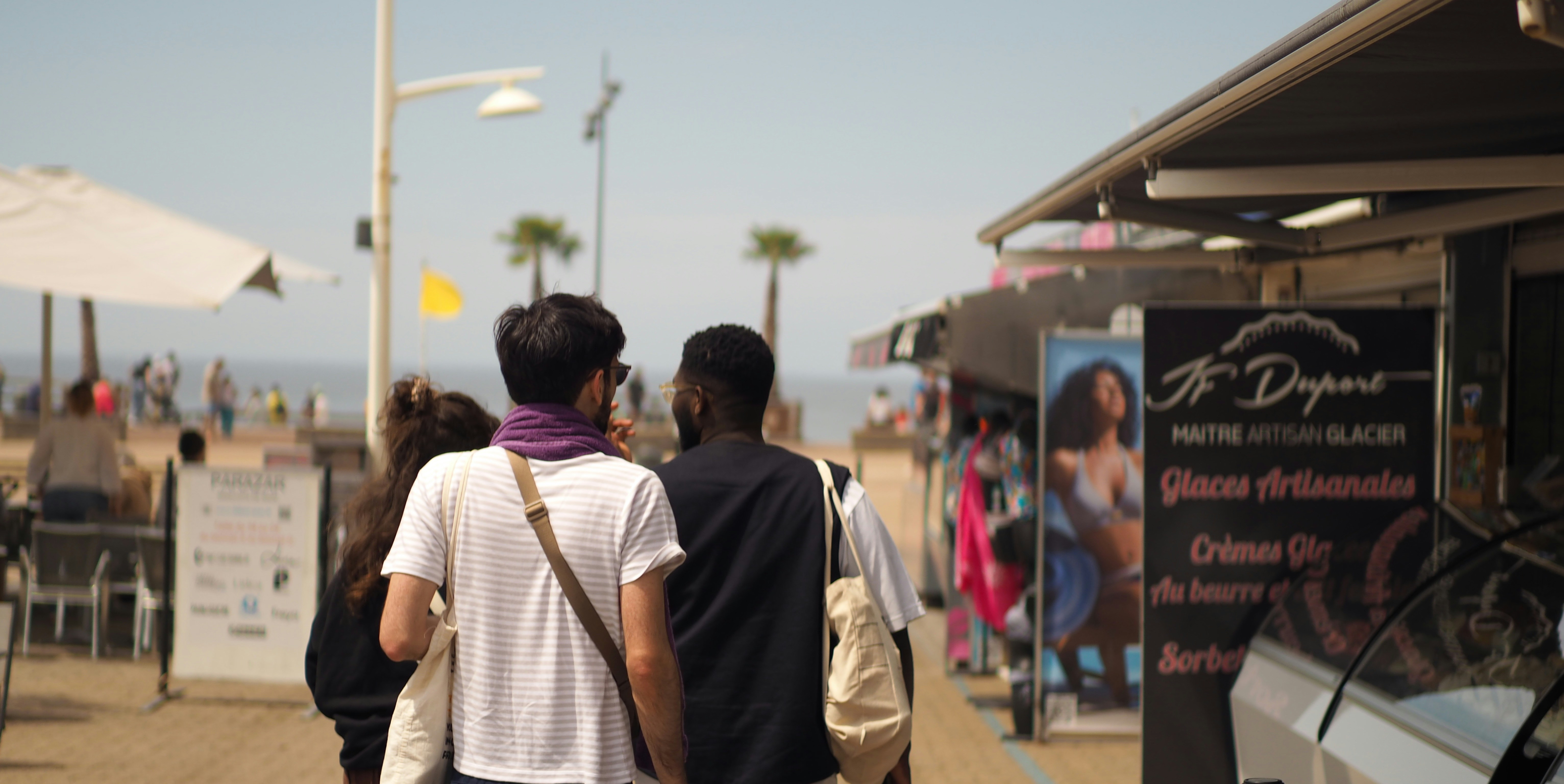 Three Pedestrians on a Sunlit Beach Boardwalk