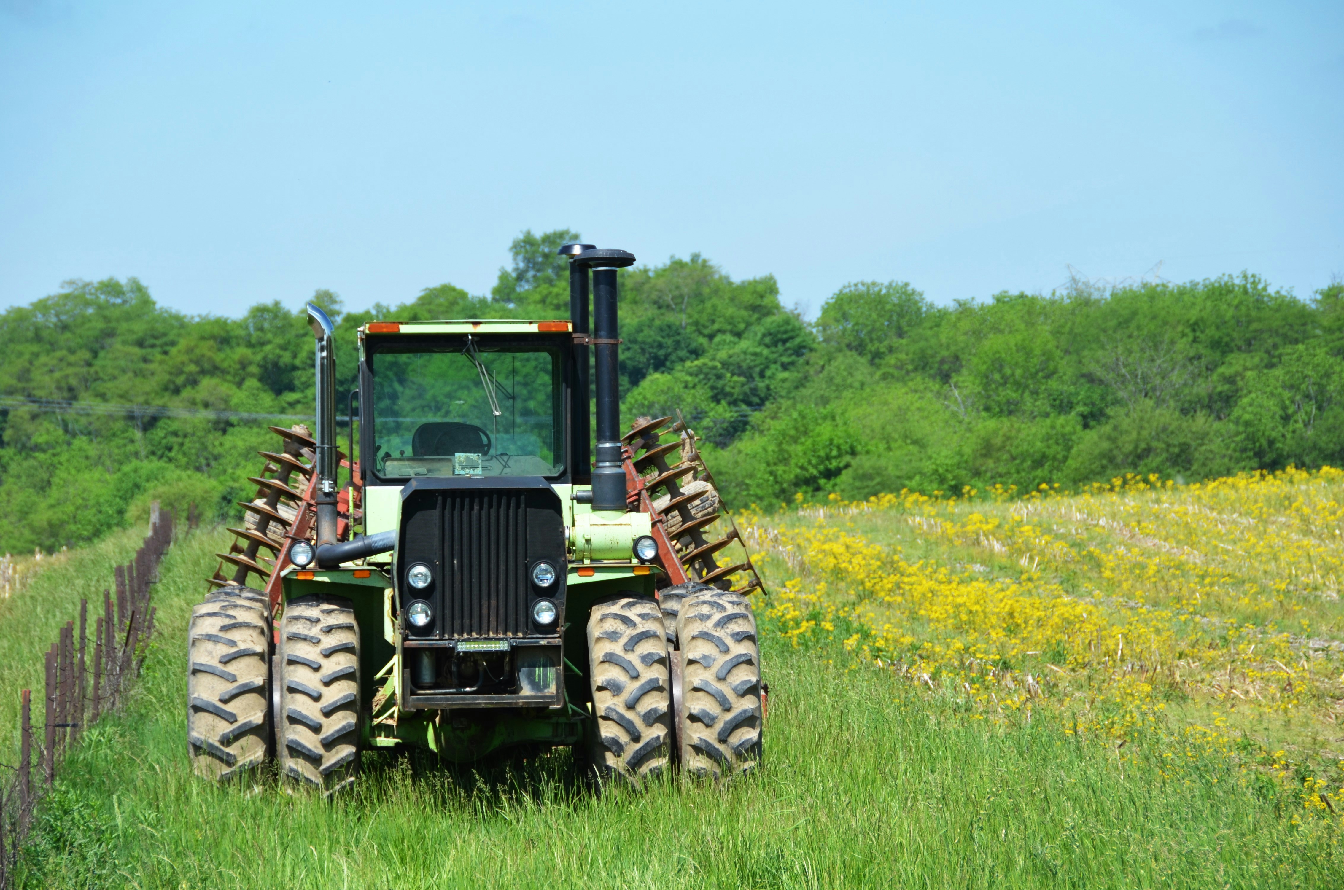 A tractor is parked in a field of tall grass photo – Free Tractor Image ...