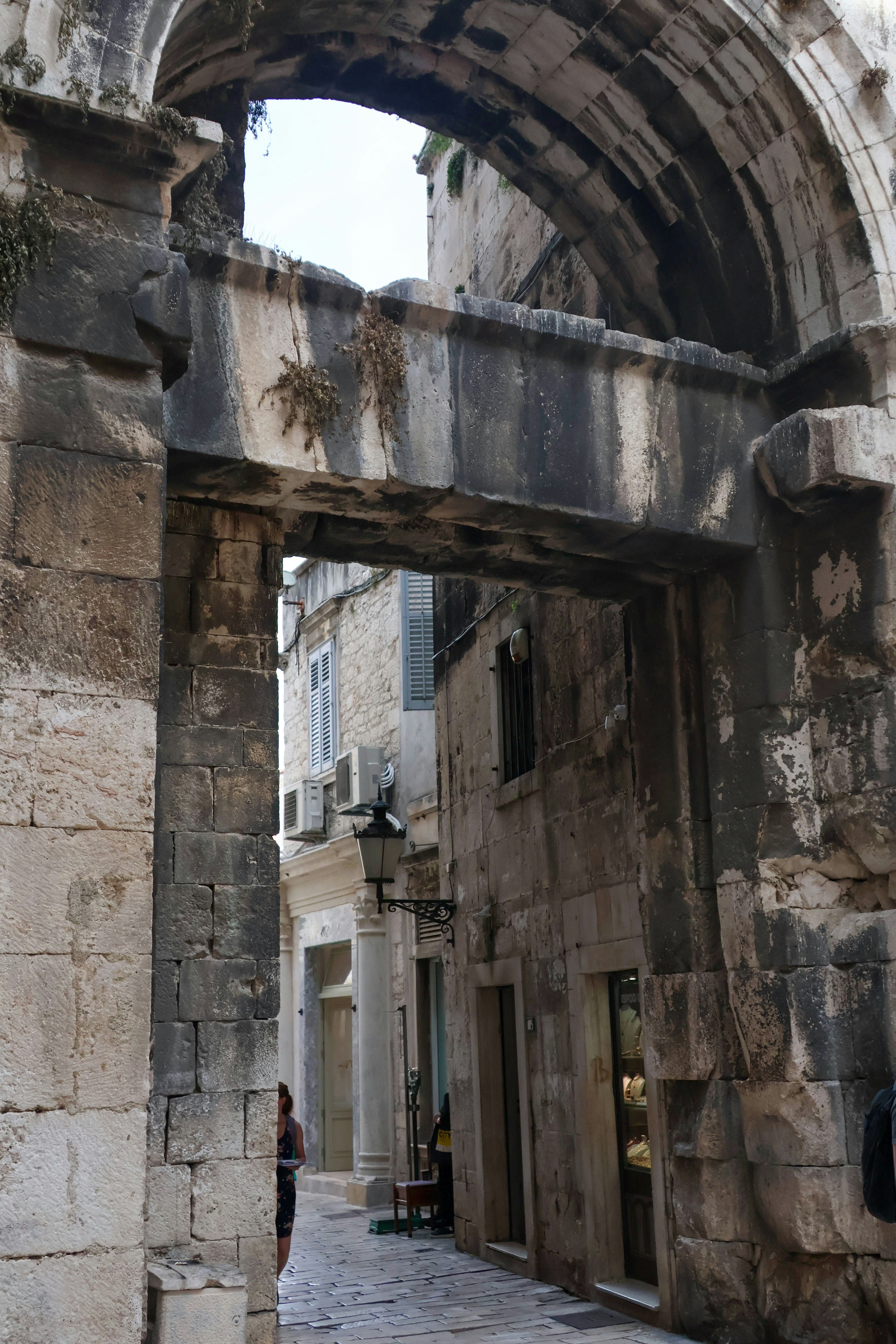 Gateway to Light: A Timeworn Archway Framing a Narrow Stone Street