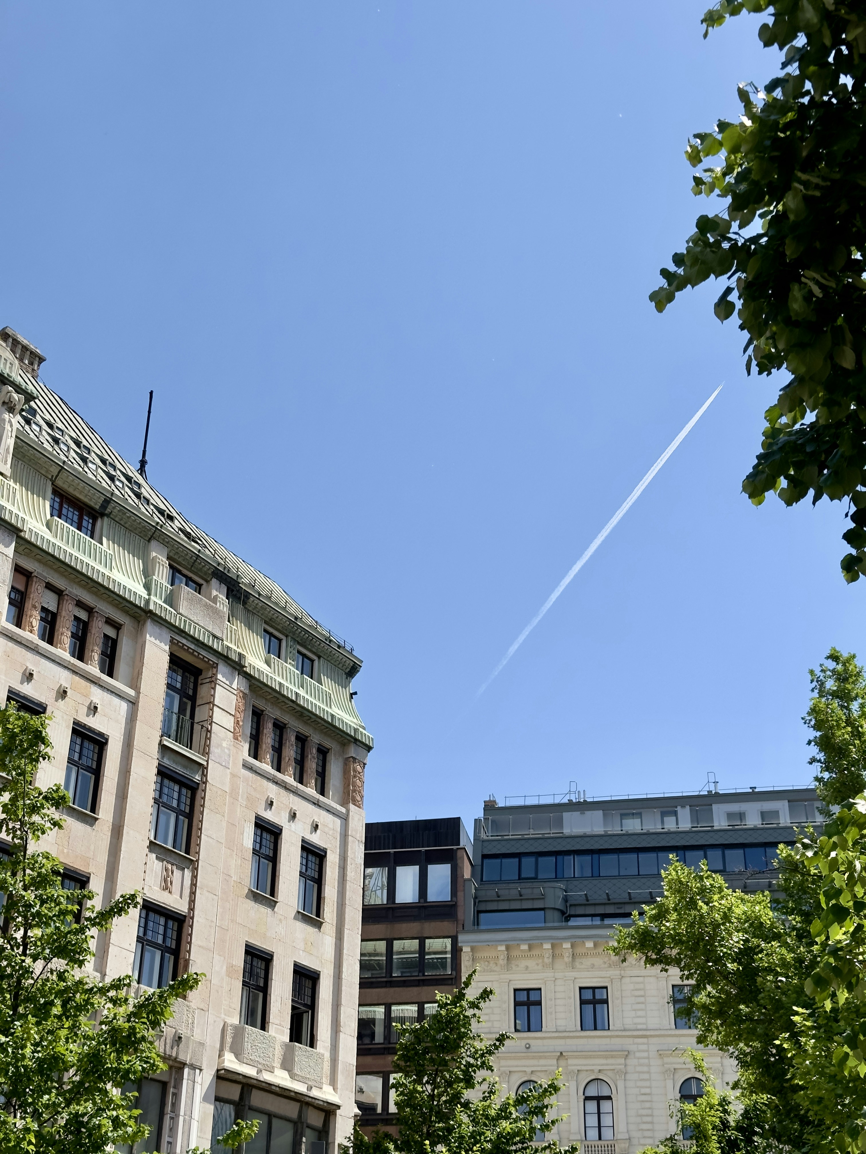 Contrail Crossing the City: Sky, Stone, and Glass