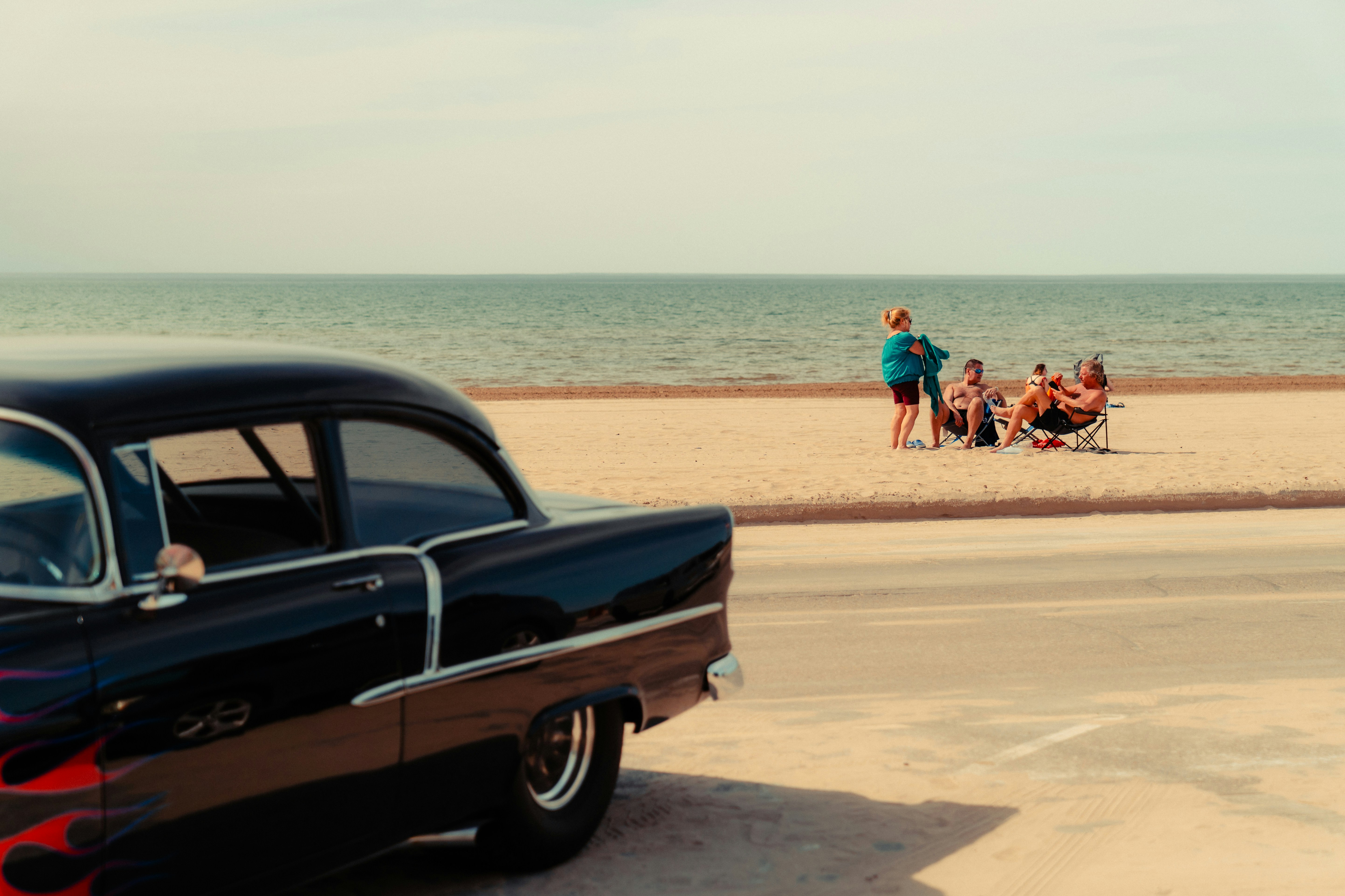a car parked on the side of the road near a beach