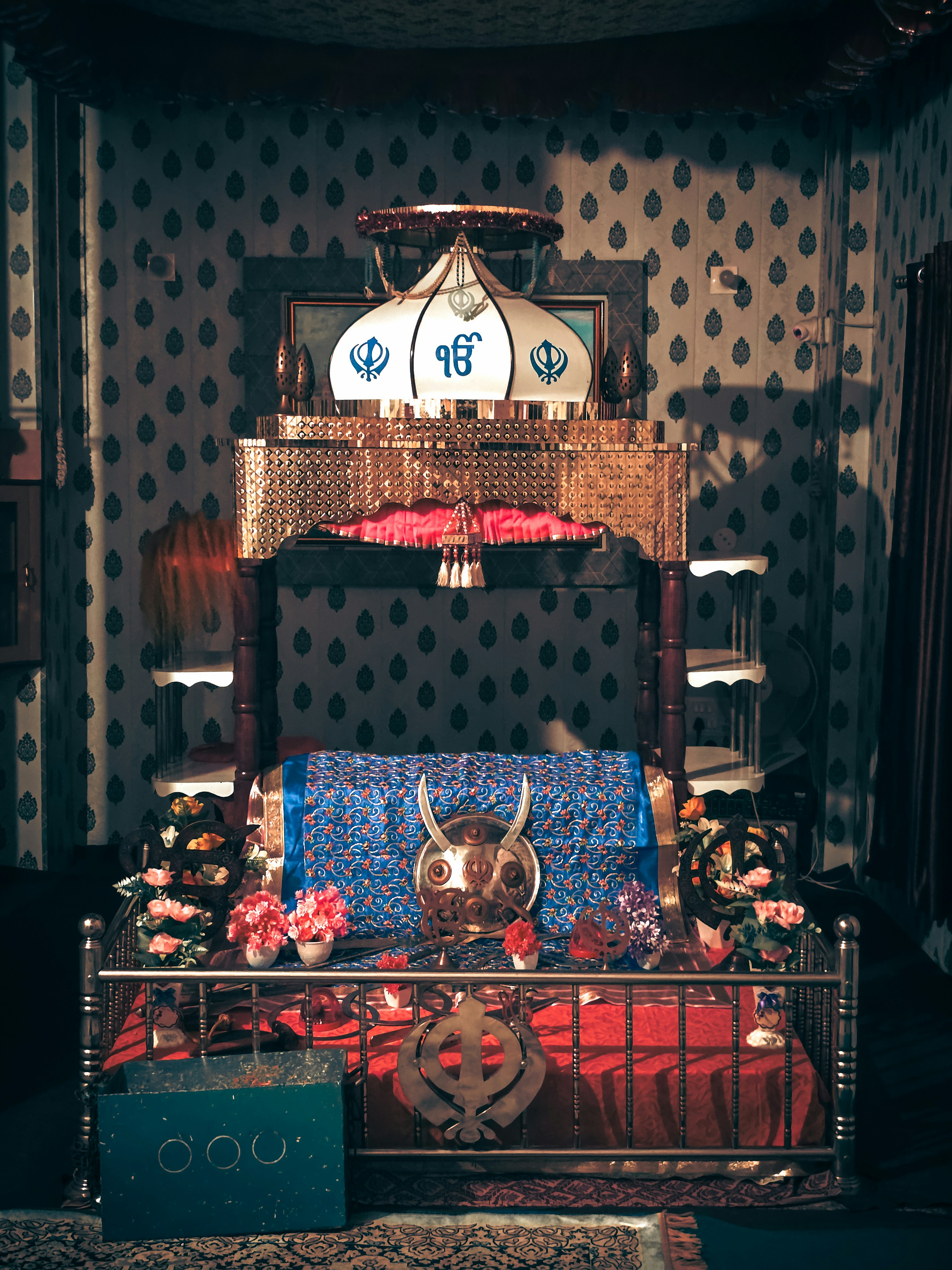 Dim Shrine Under Velvet Canopy: Horned Mask on a Blue Textile Altar